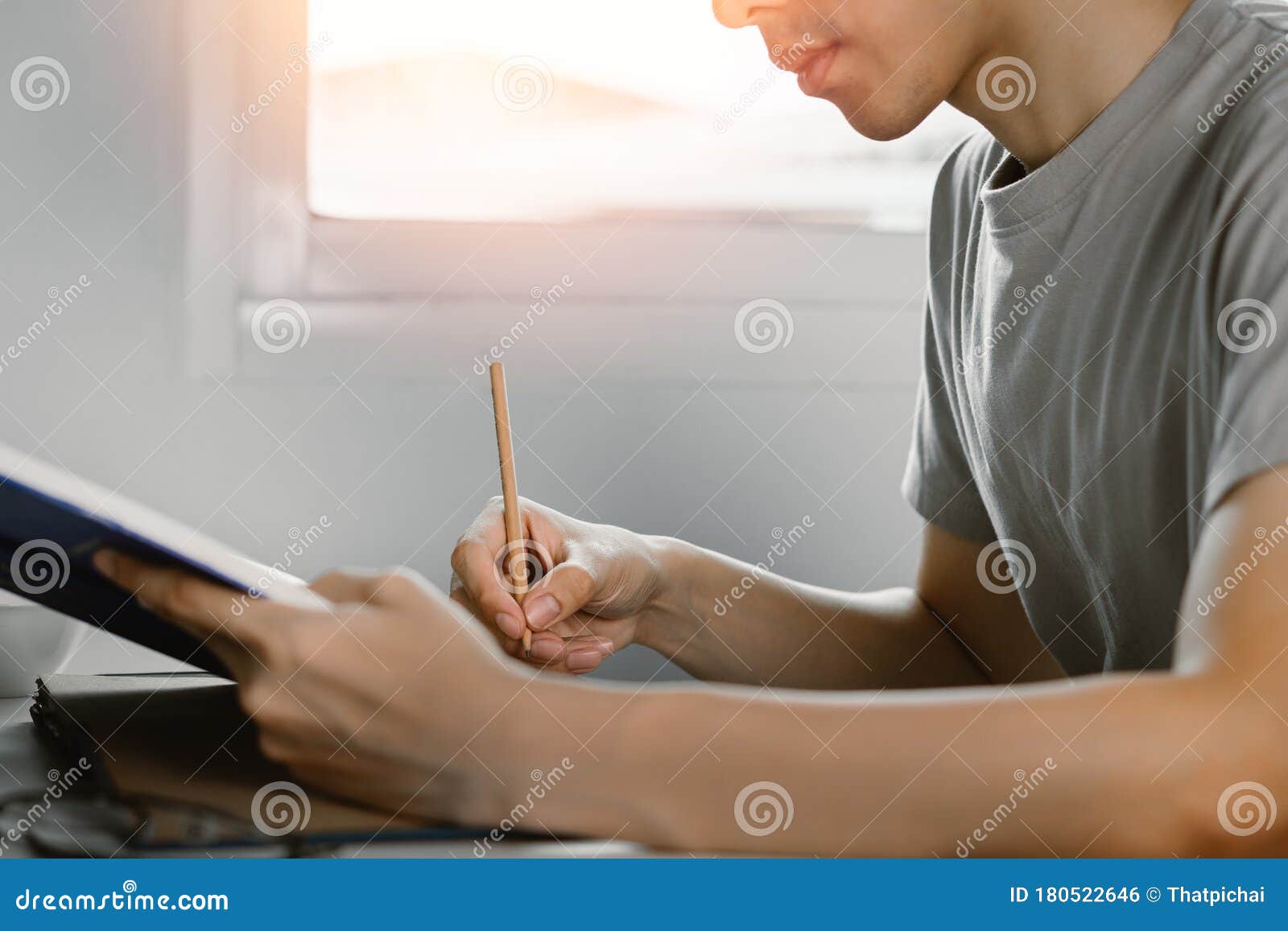 Young Man Reading Book and Writing in Note at Work Desk in Free Time ...
