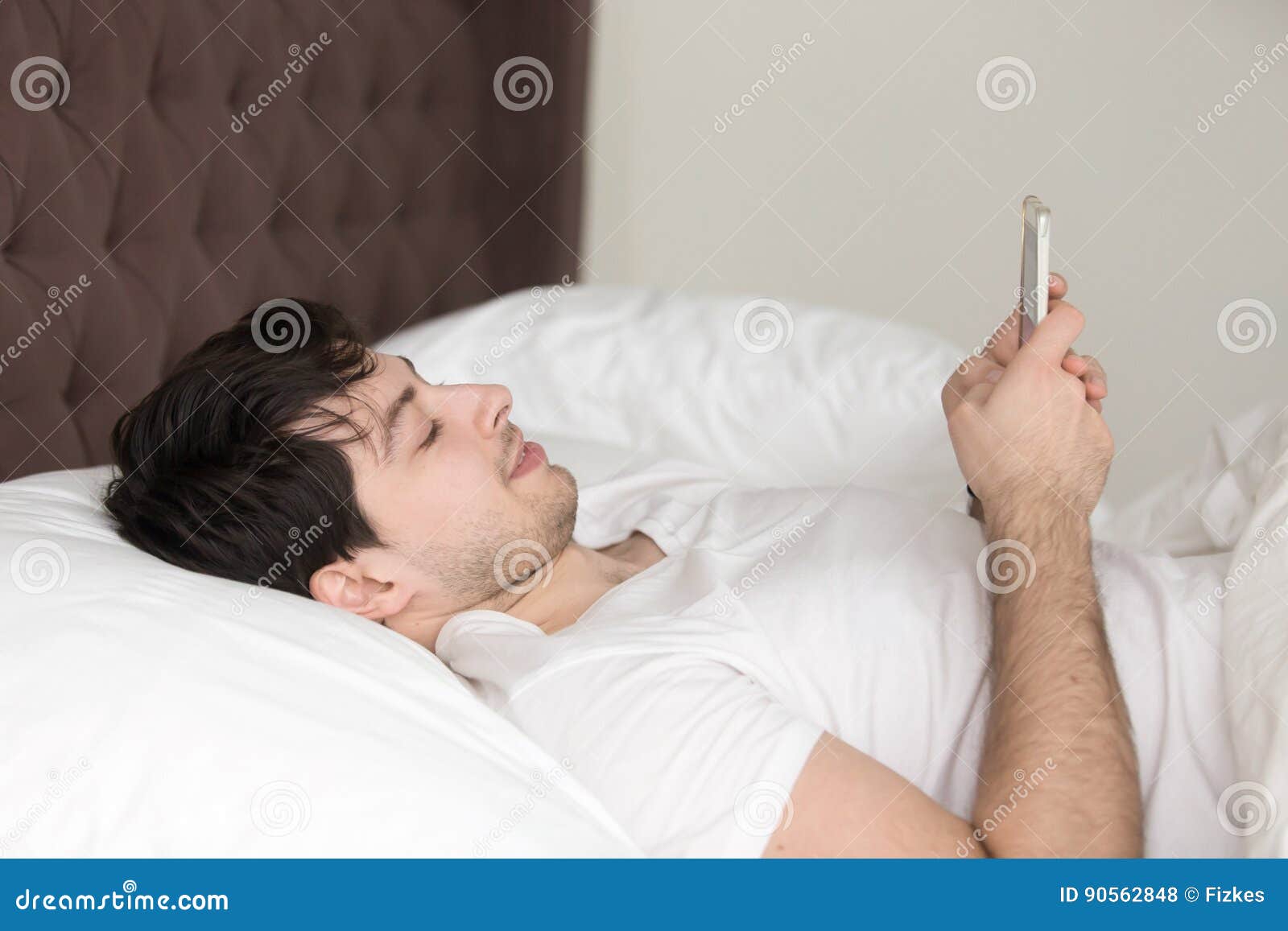 Young Man Relaxing in Bed at Home Using Mobile Smartphone Stock Photo ...