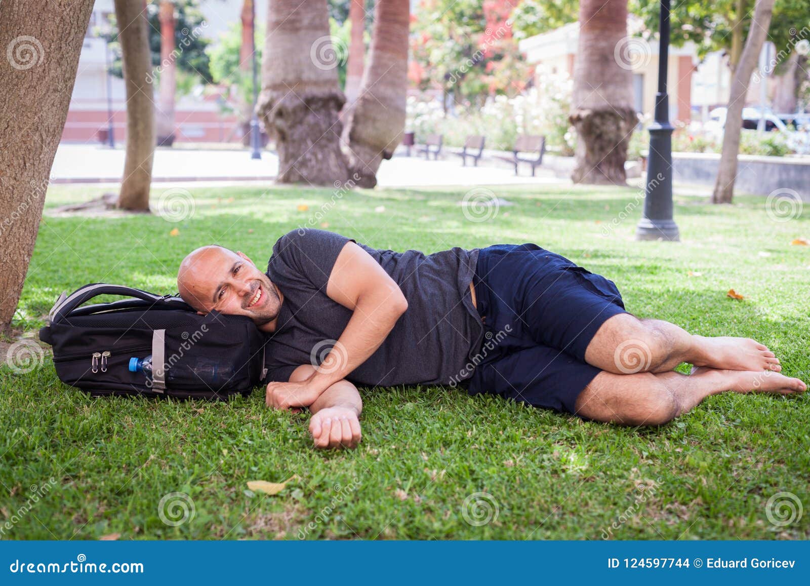 A Young Man is Relaxing in a Park Under a Tree with a Backpack U Stock ...