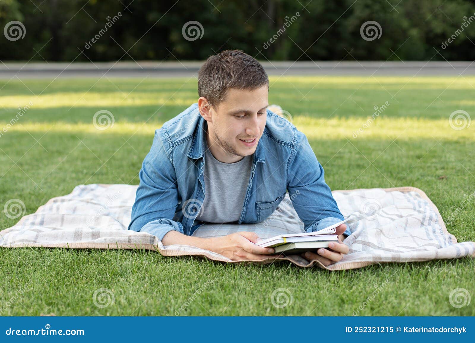 Young Man Relaxing And Reading Book While Lying On Lawn Happy Man