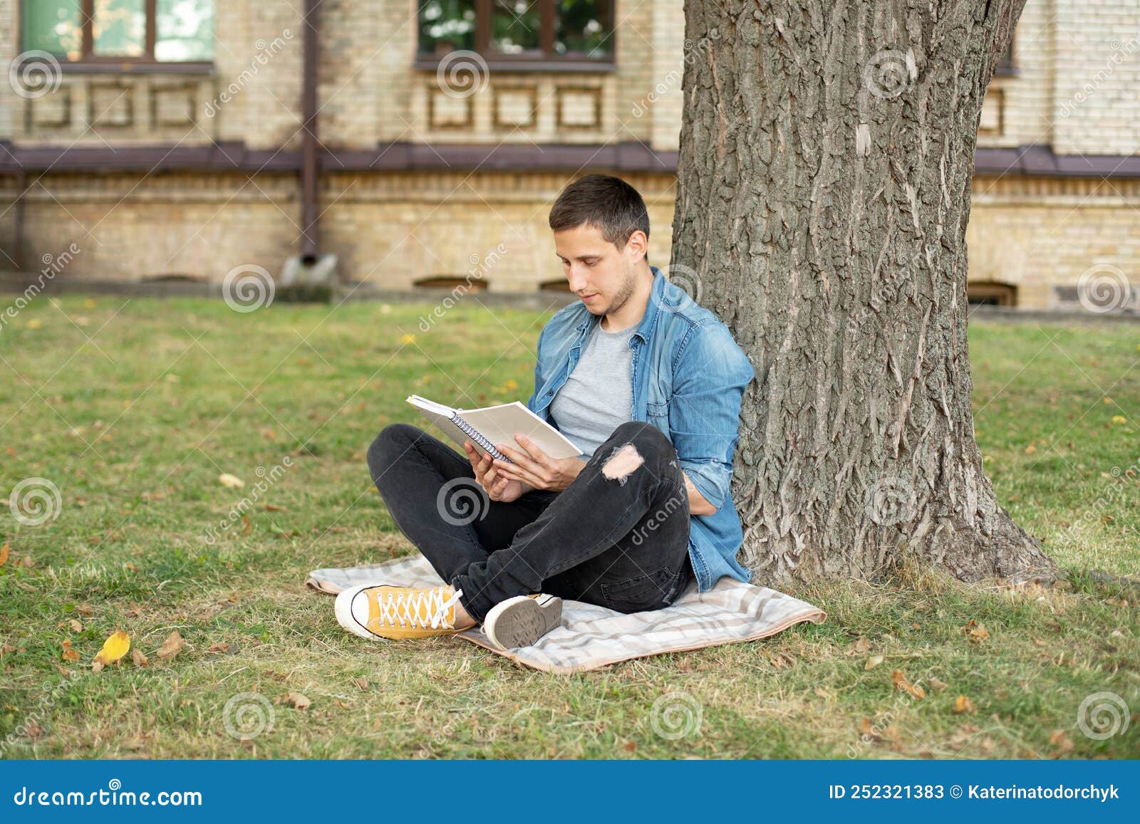 Young Man Relaxing And Reading Book While Sit On Lawn Happy Man