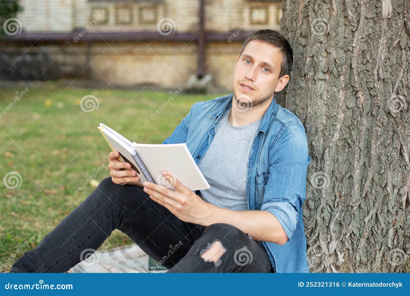 Young Man Relaxing And Reading Book While Sit On Lawn Happy Man