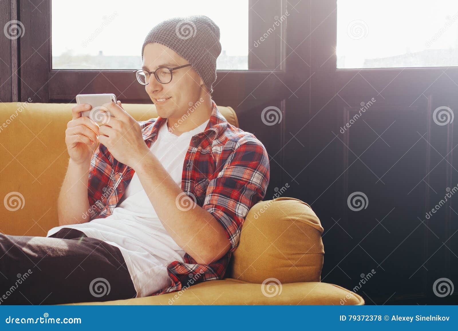 Young Man Relaxing on Sofa and Looking at His Smart Phone Stock Photo ...