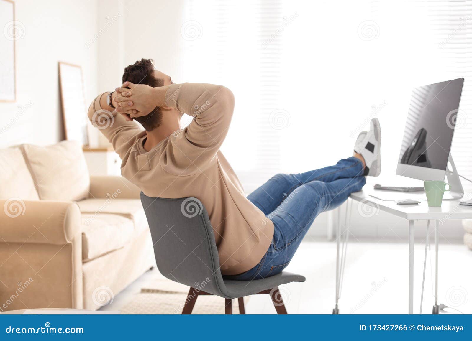 Young Man Relaxing at Table in Office Stock Photo - Image of monitor ...