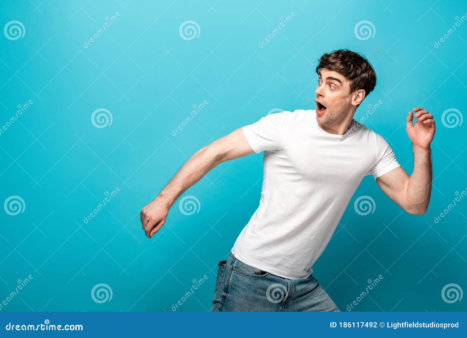 Young Man Running Away and Looking Back on Blue Background Stock Photo ...