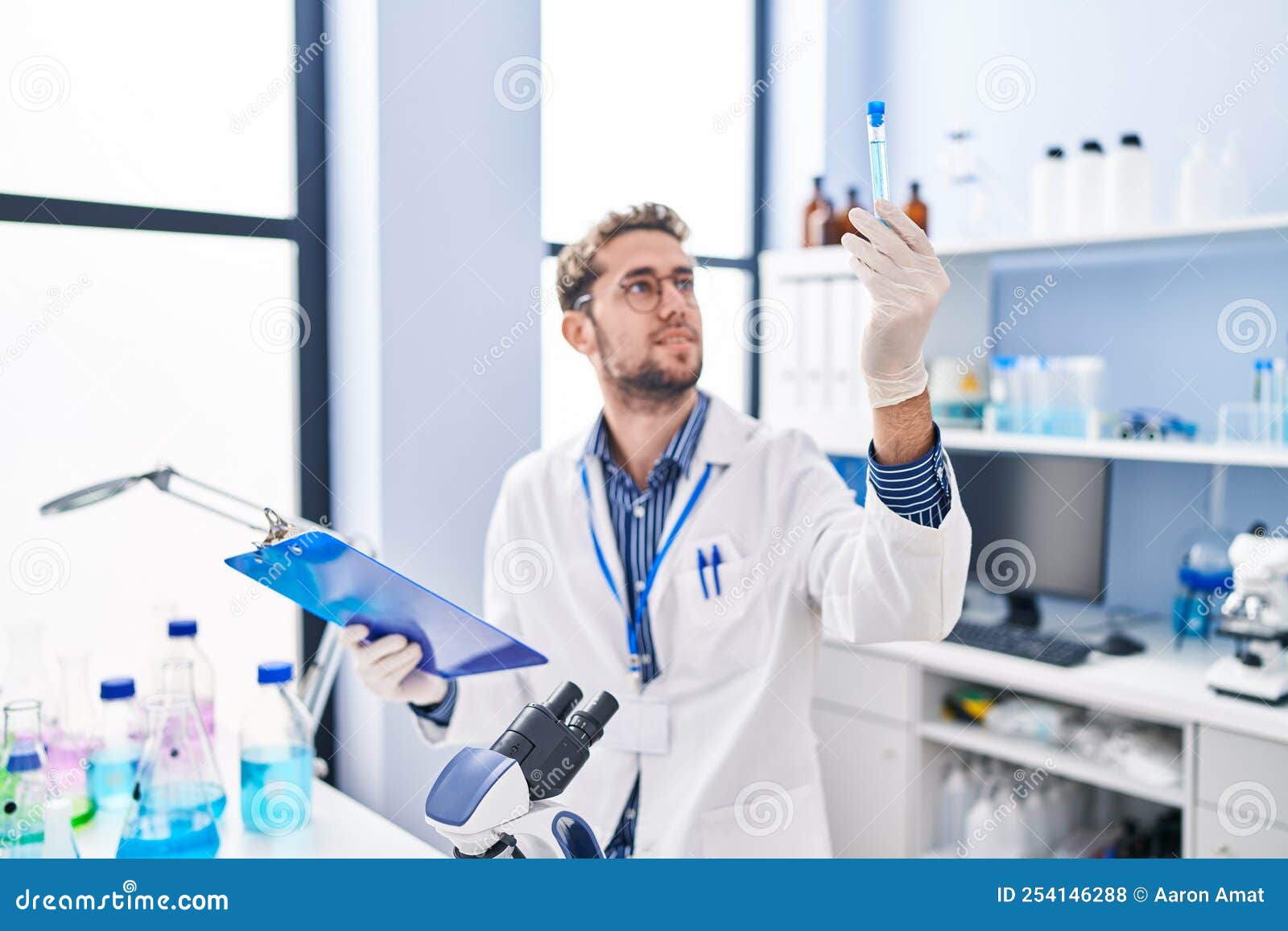 Young Man Scientist Reading Report Holding Test Tube at Laboratory ... Young Man Scientist Reading Report Holding Test Tube at Laboratory ...