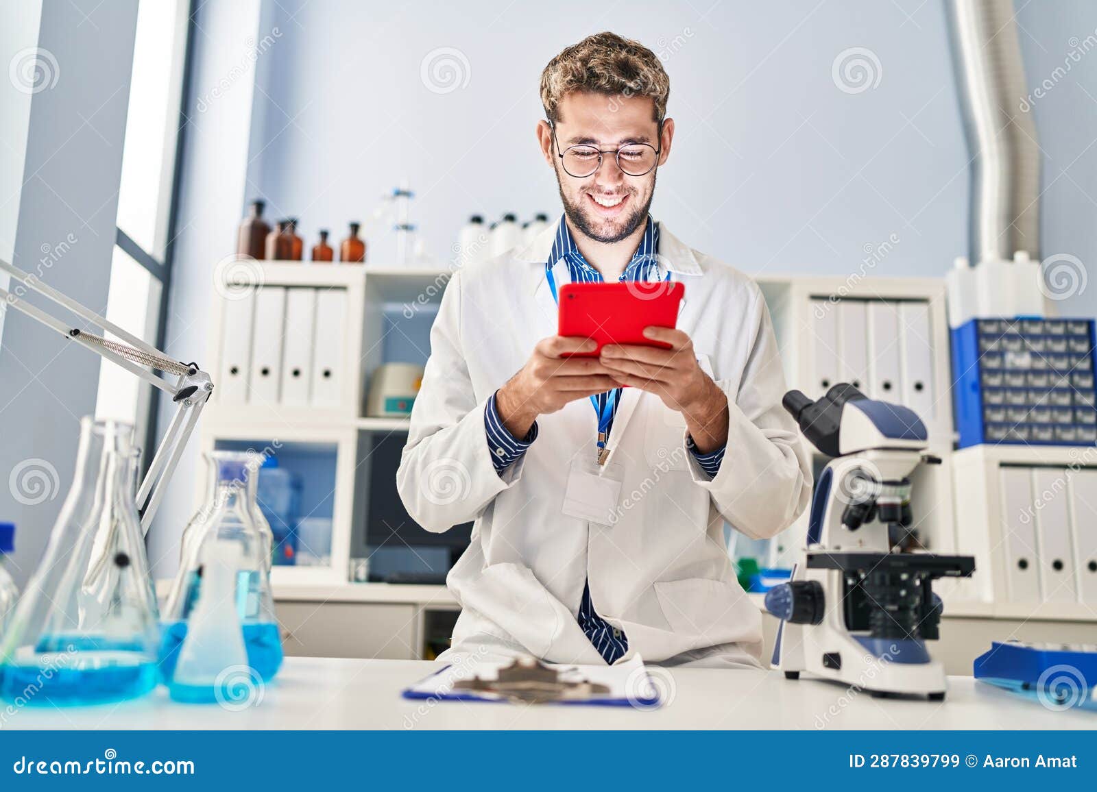 Young Man Scientist Smiling Confident Using Touchpad at Laboratory ... Young Man Scientist Smiling Confident Using Touchpad at Laboratory ...