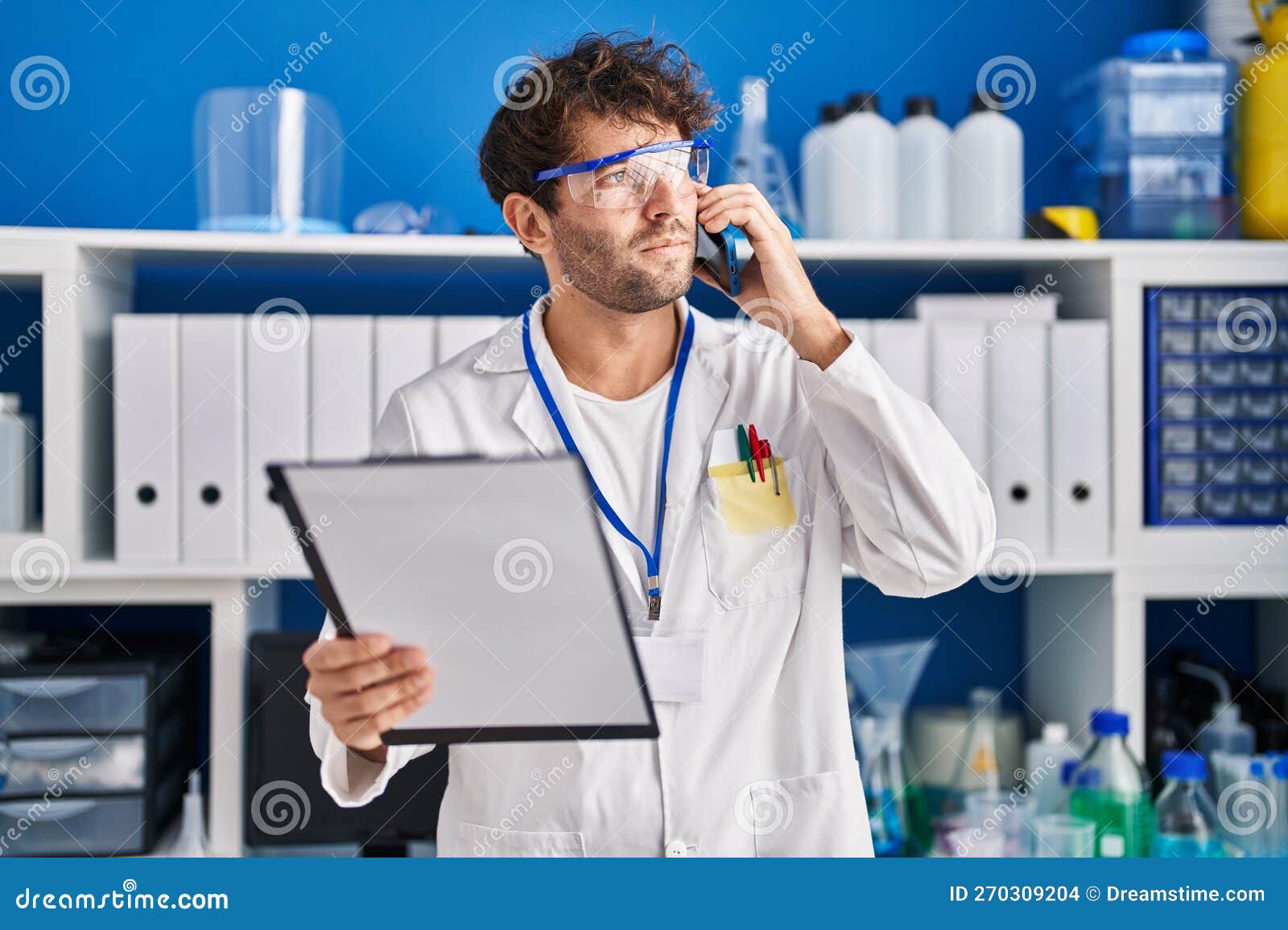 Young Man Scientist Talking on Smartphone Holding Clipboard at ...