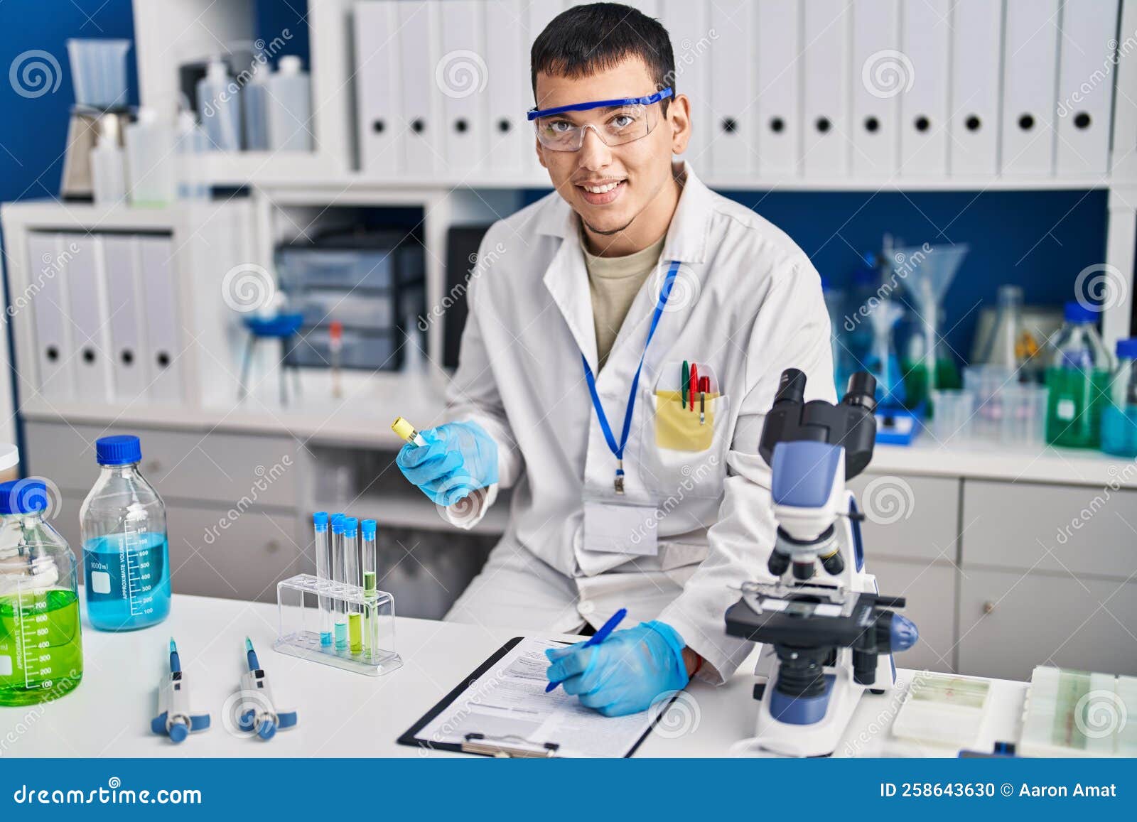 Young Man Scientist Writing on Document Measuring Liquid at Laboratory ...