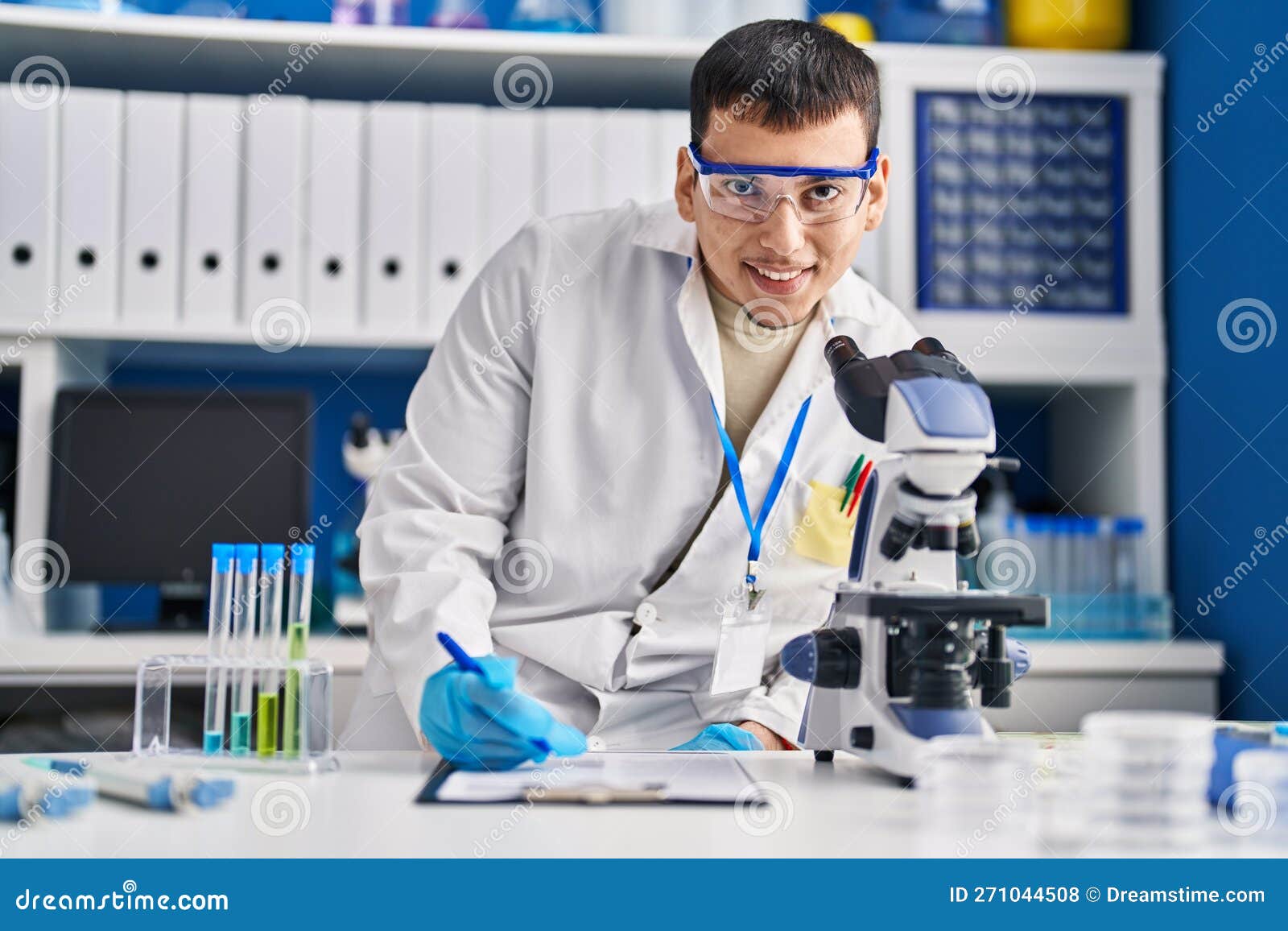 Young Man Scientist Writing on Document Using Mircoscope at Laboratory ...