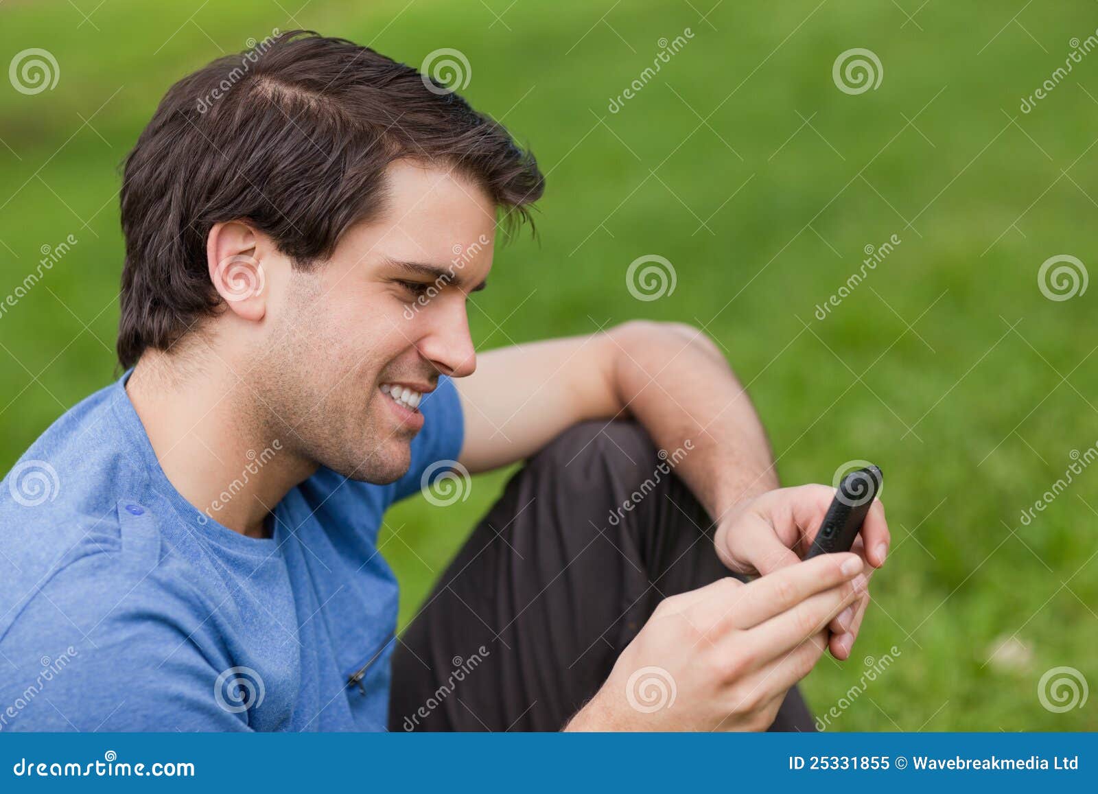 Young Man Sending a Text with His Cellphone while Sitting on the Stock ...