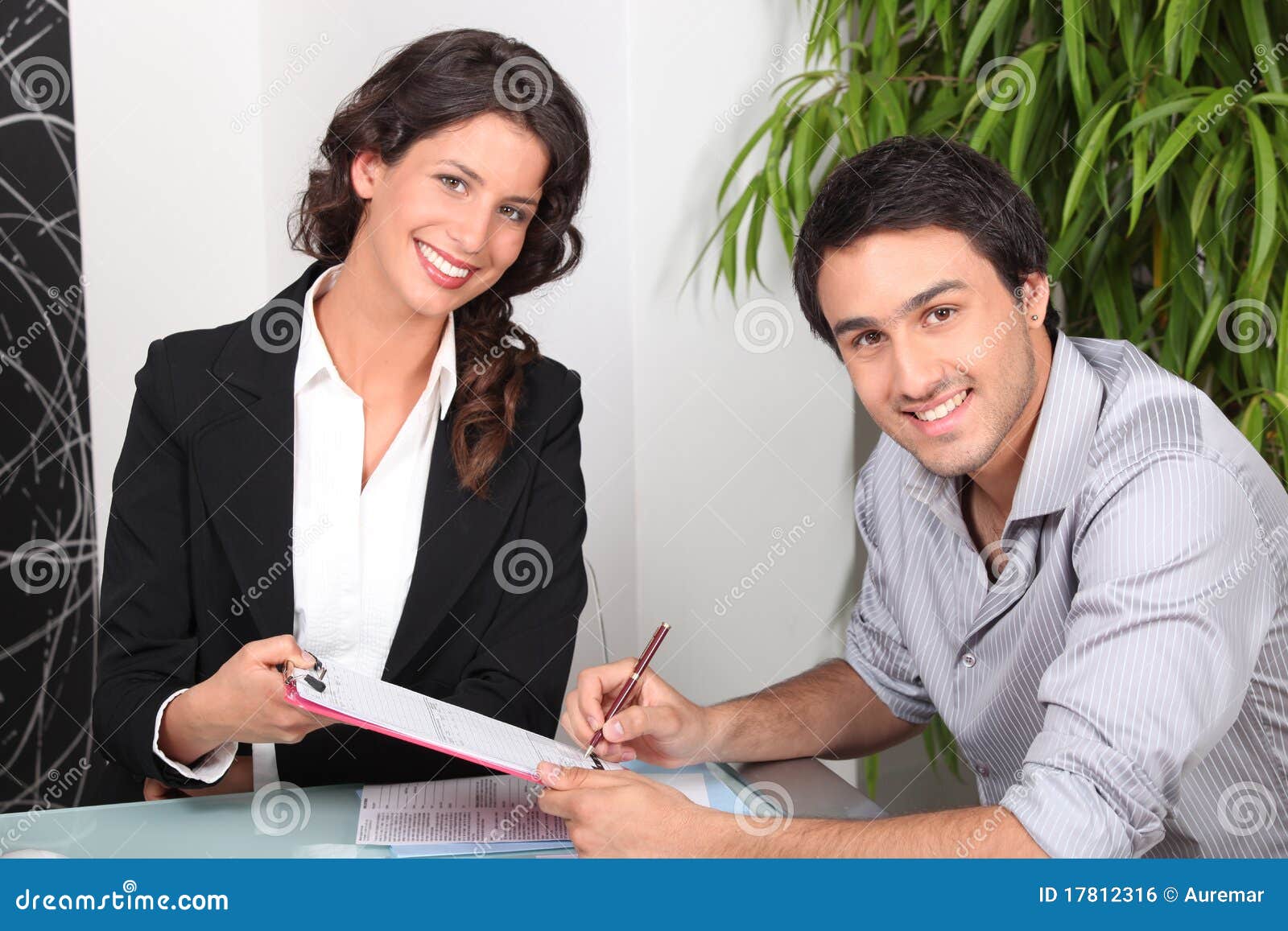 Young Man Signing Document and Young Woman Smiling Stock Photo - Image ...
