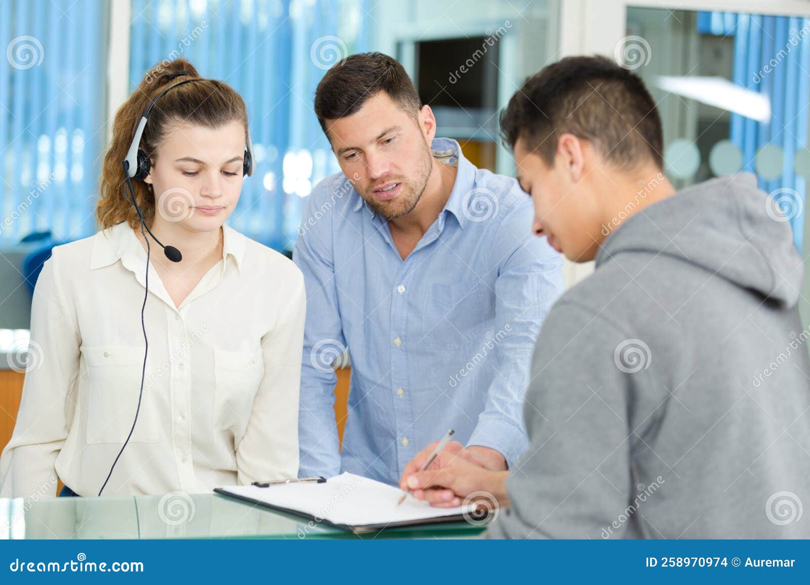Young Man Signing Paperwork at Reception Stock Photo - Image of ...