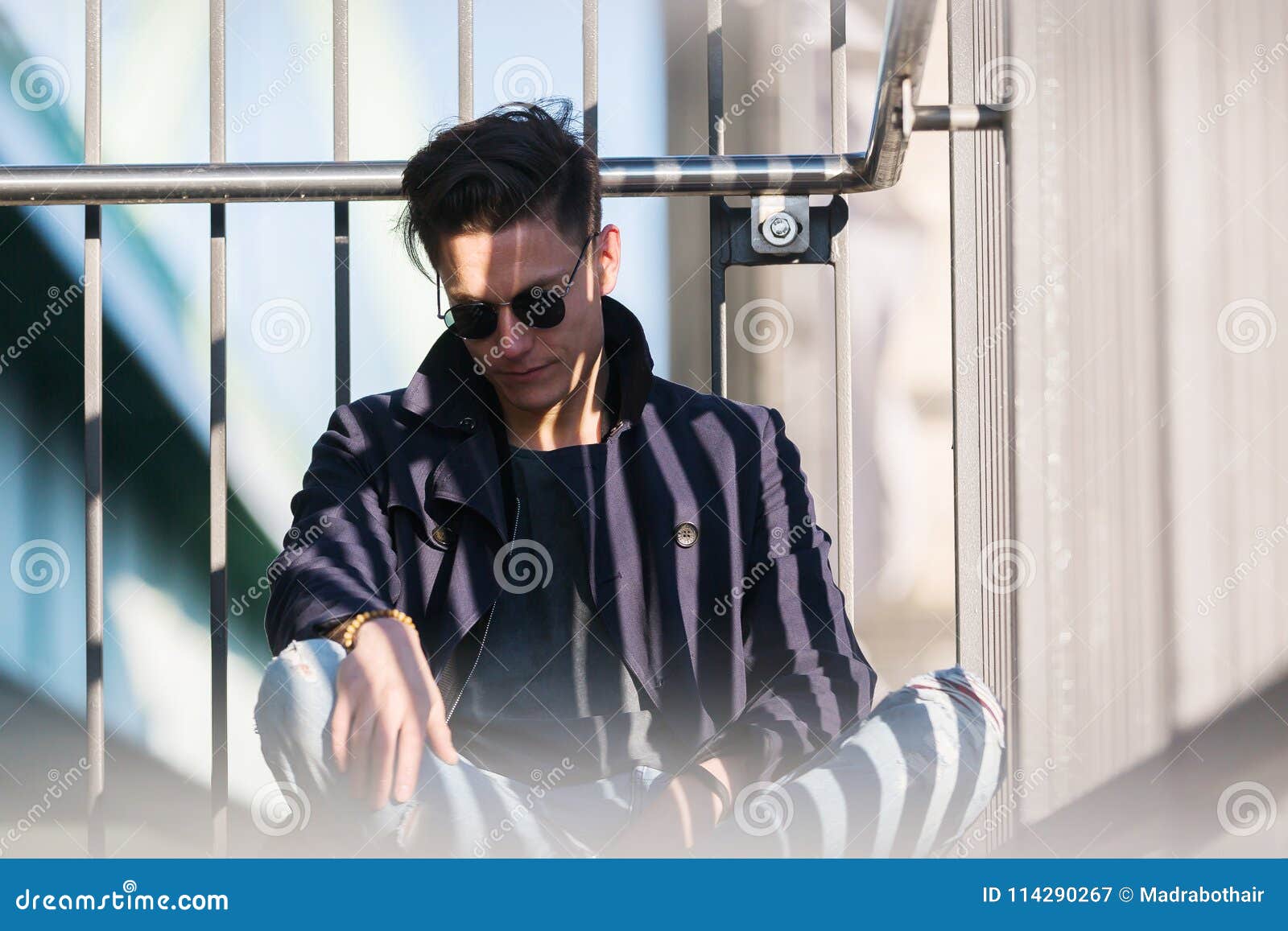 Young Man Sits beside a Handrail Stock Image - Image of looking, jeans ...
