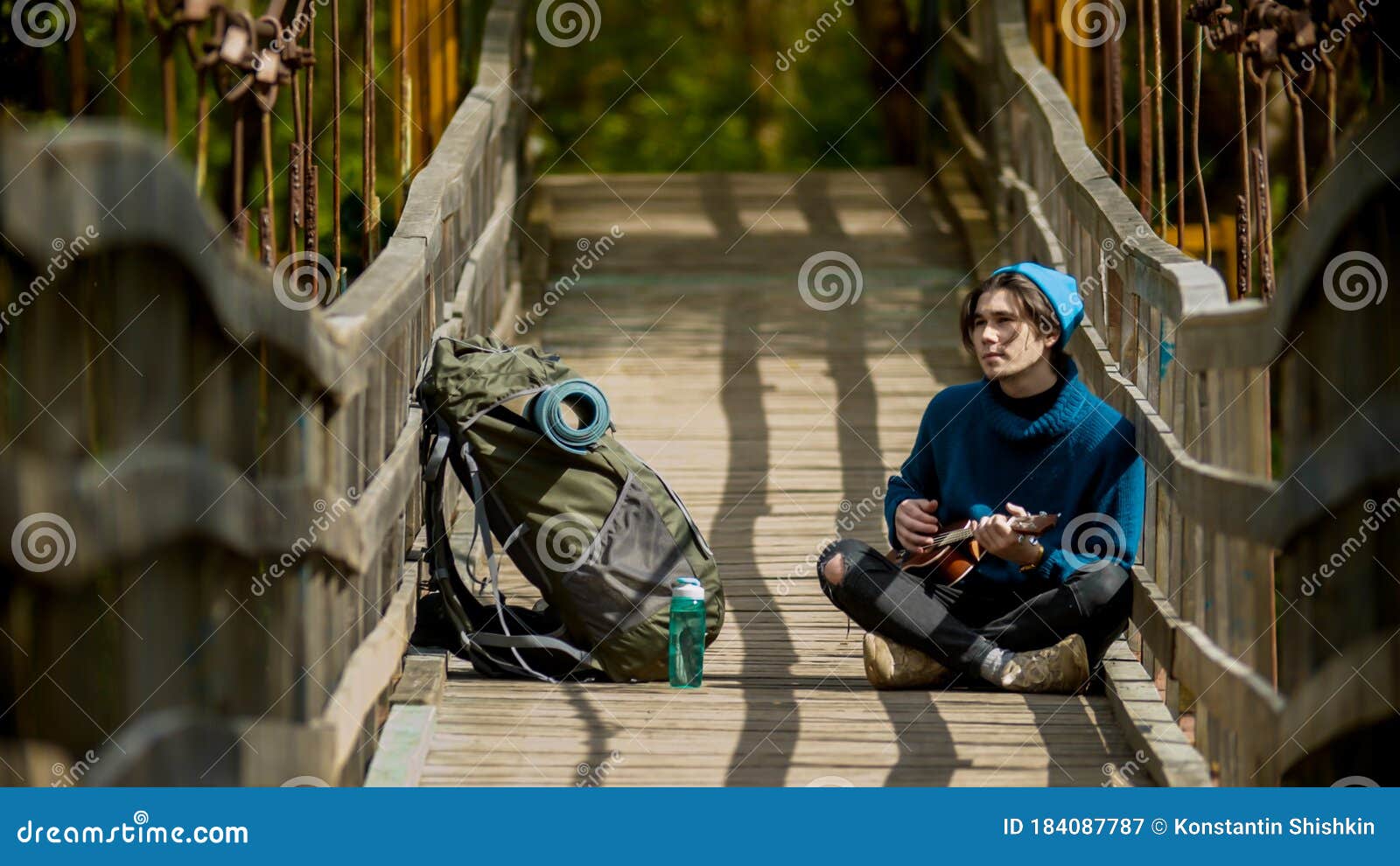 Young Man Sitting on the Bridge and Playing Ukulele Stock Image - Image ...