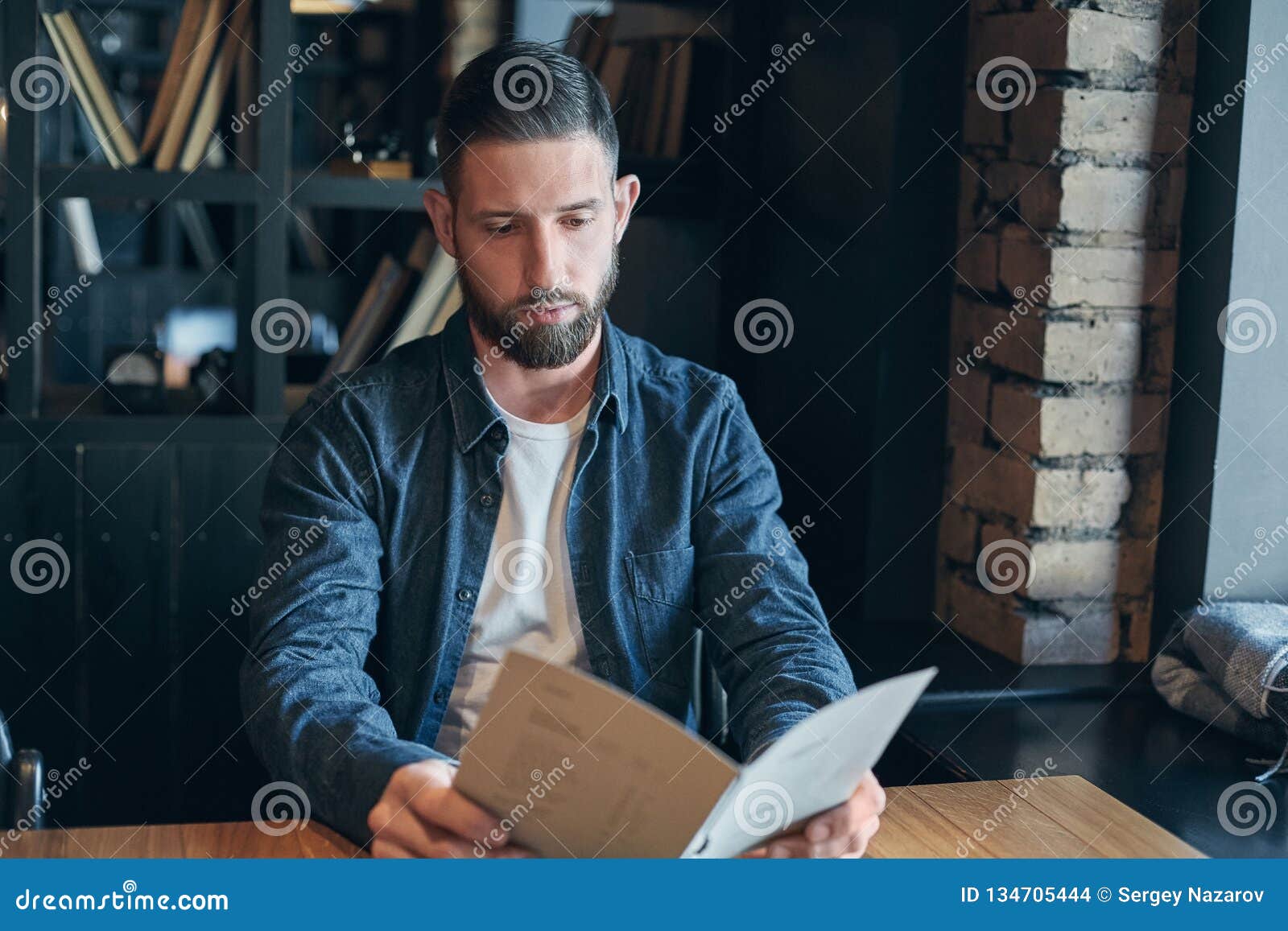 Young Man Sitting in a Cafe at the Table and Watching the Menu To Make ...