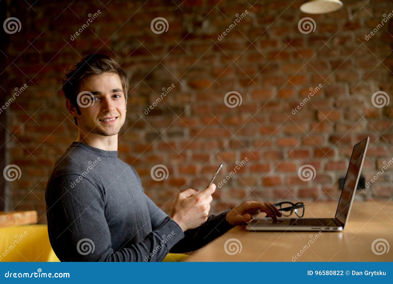 Young Man Sitting in Cafe and Using Laptop and Mobile Phone Stock Photo ...