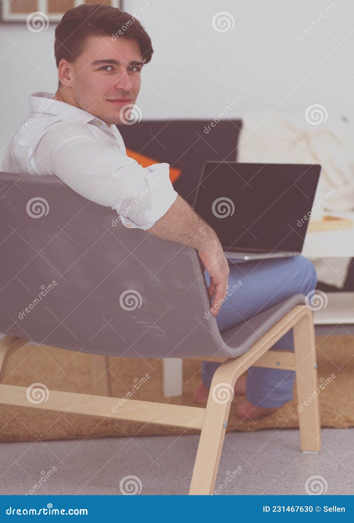 Young Man Sitting in Chair and Working on Laptop Computer Stock Photo ...