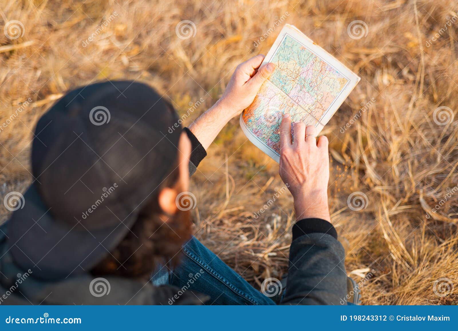 A Young Man is Sitting on the Field and Looking in a Map Stock Photo ...