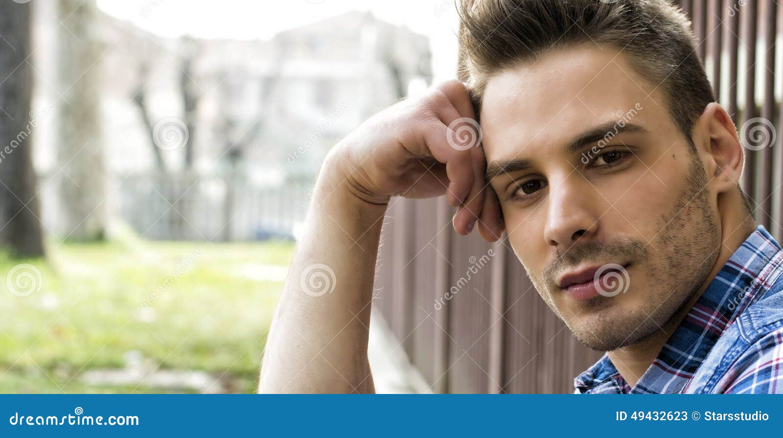 Young Man Sitting on Ground Outside, Looking at Camera Stock Image ...