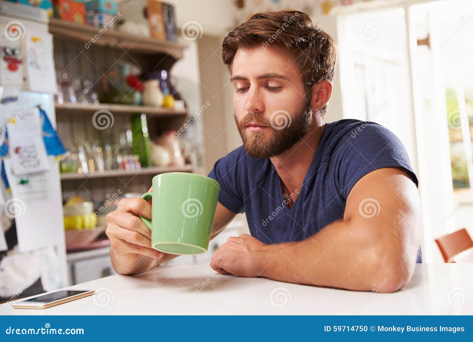 Young Man Sitting at Kitchen Table Drinking Coffee Stock Photo - Image ...