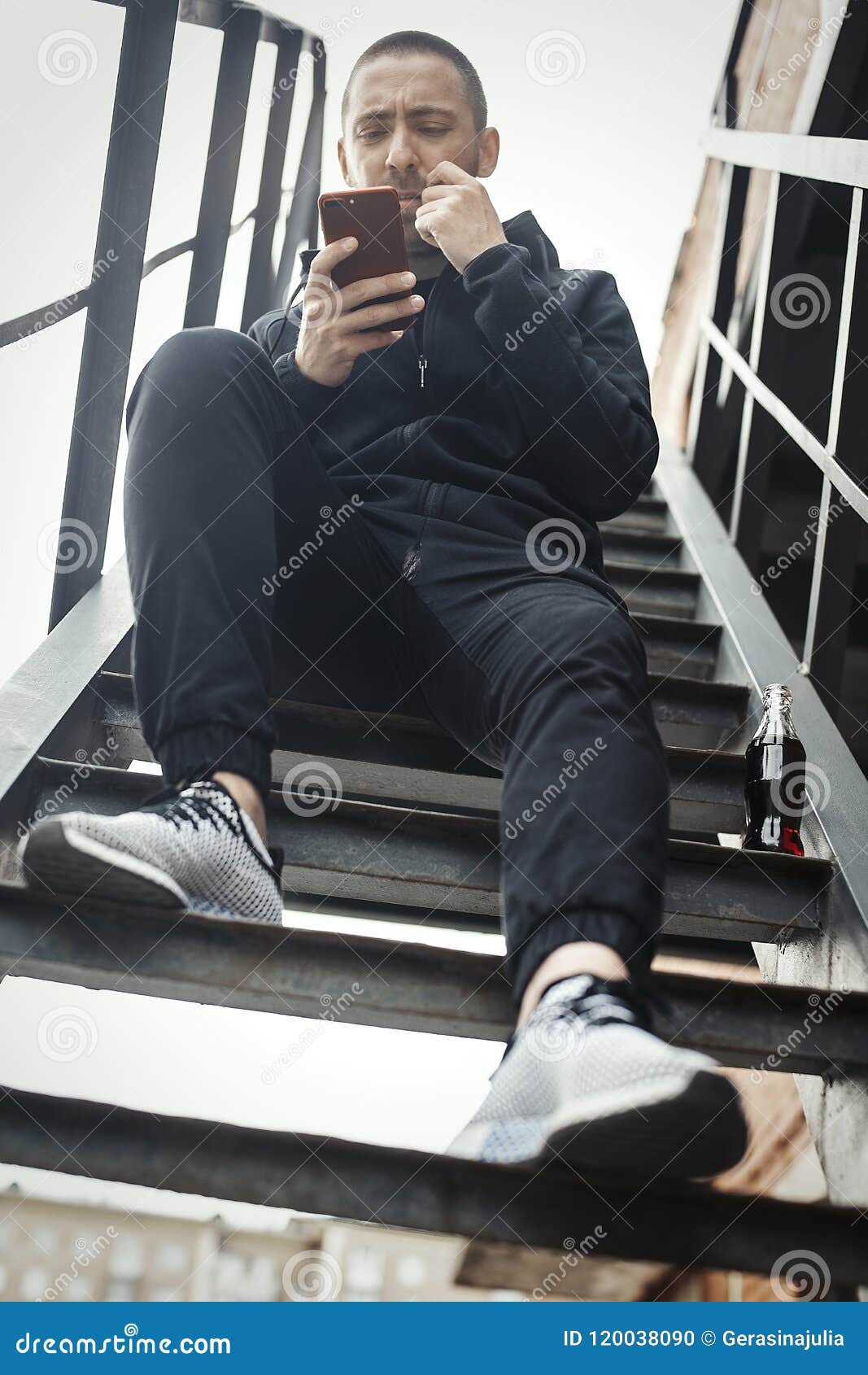 Young Man Sitting on a Ladder and Watching His Mobile Phone. Stock ...