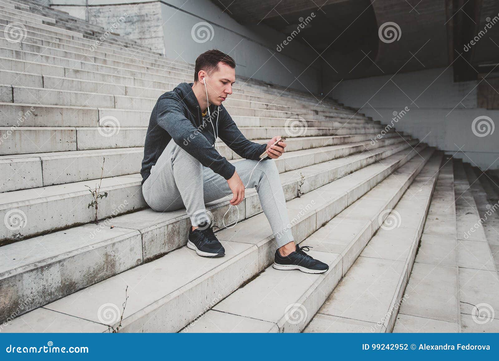 Young Man Sitting on the Modern Bridge in the City, Using His ...