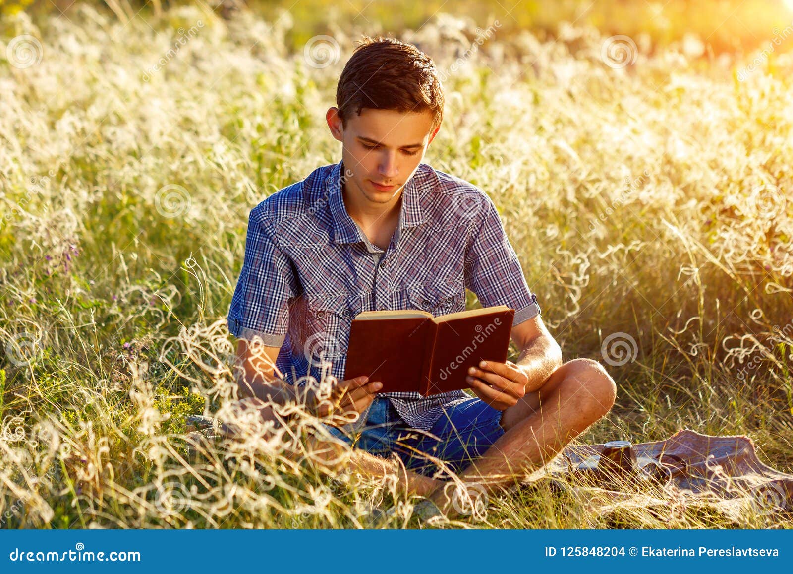 Young Man Sitting in Nature Reading a Book Stock Photo - Image of ...