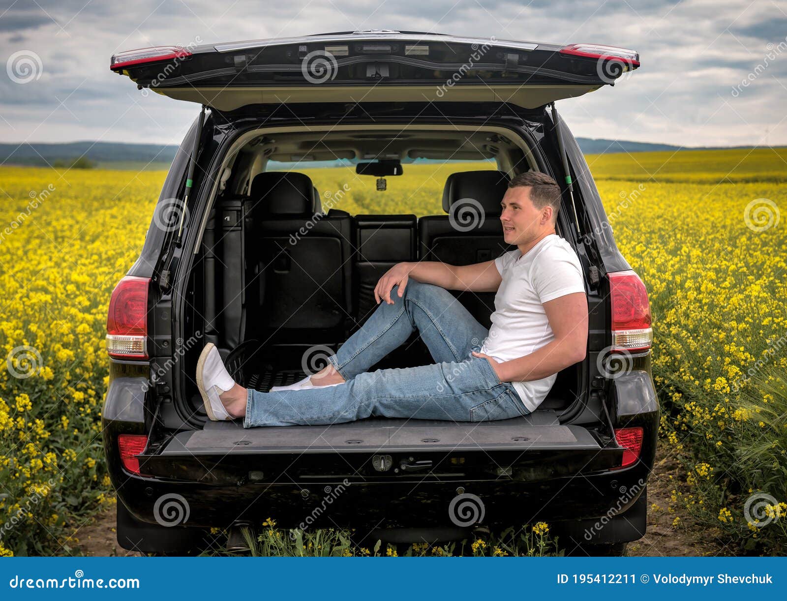 Young Man Sitting in the Opened Trunk of a Car in Field Stock Image ... Young Man Sitting in the Opened Trunk of a Car in Field Stock Image ...