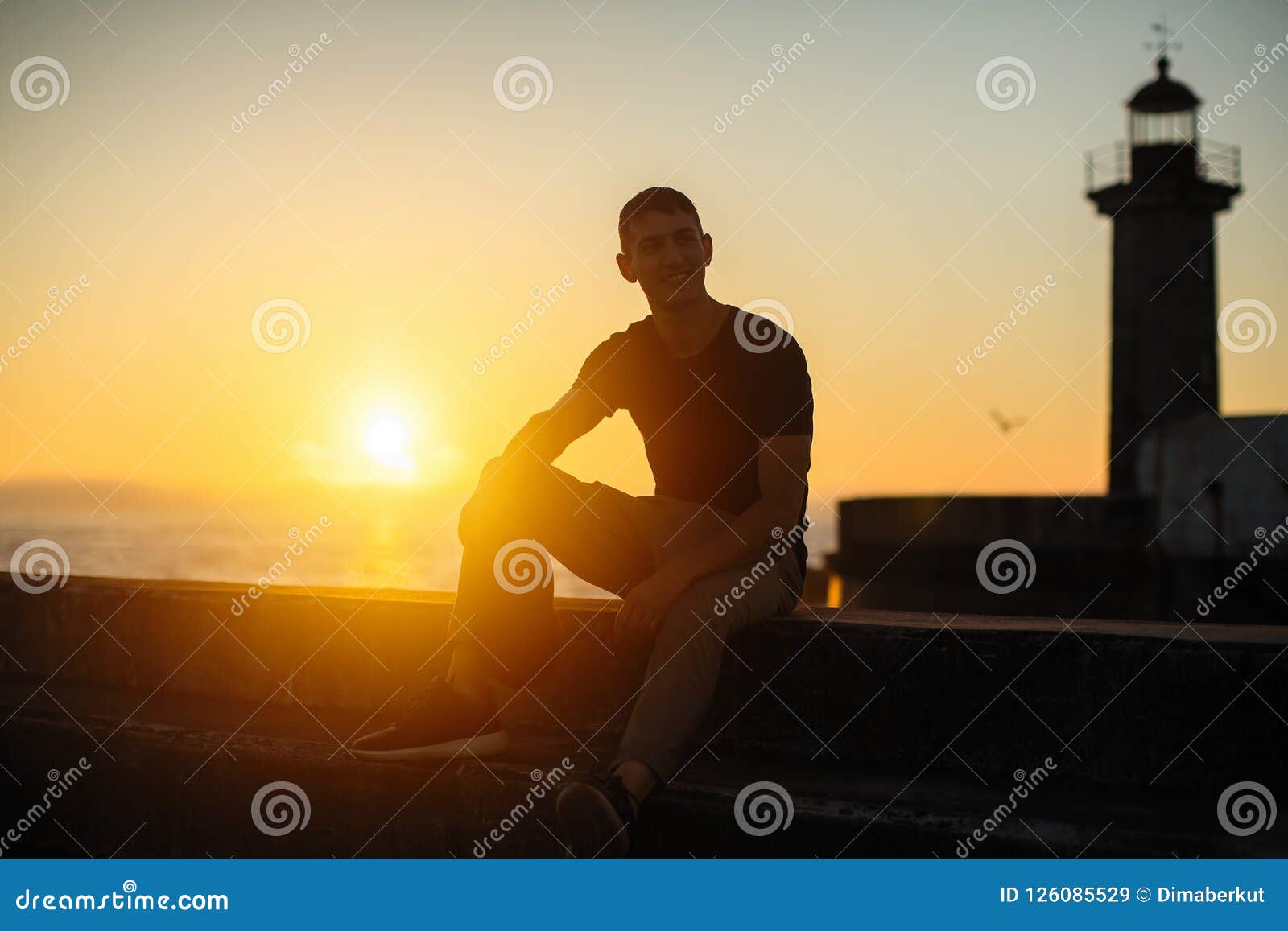 Young Lone Man Sitting on the Seaside Promenade in the Sunset. Stock ...