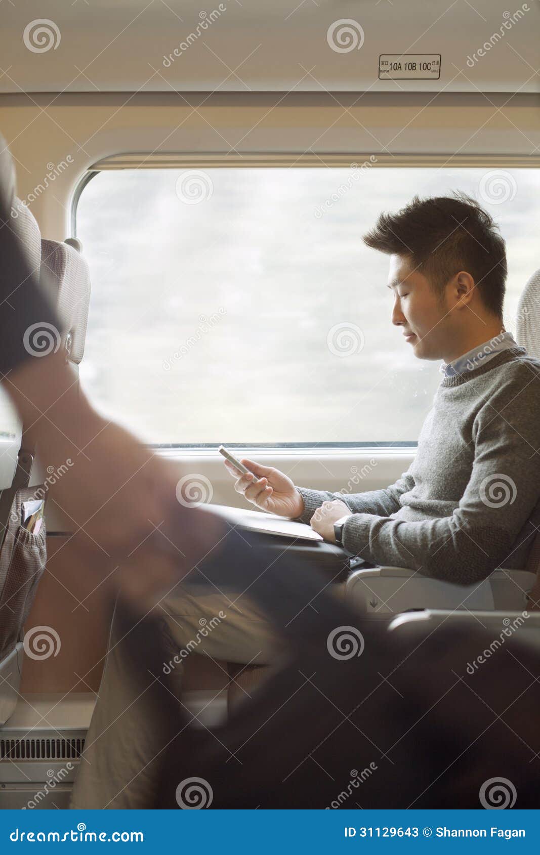 Young Man Sitting on a Train Using His Phone Stock Image - Image of ...