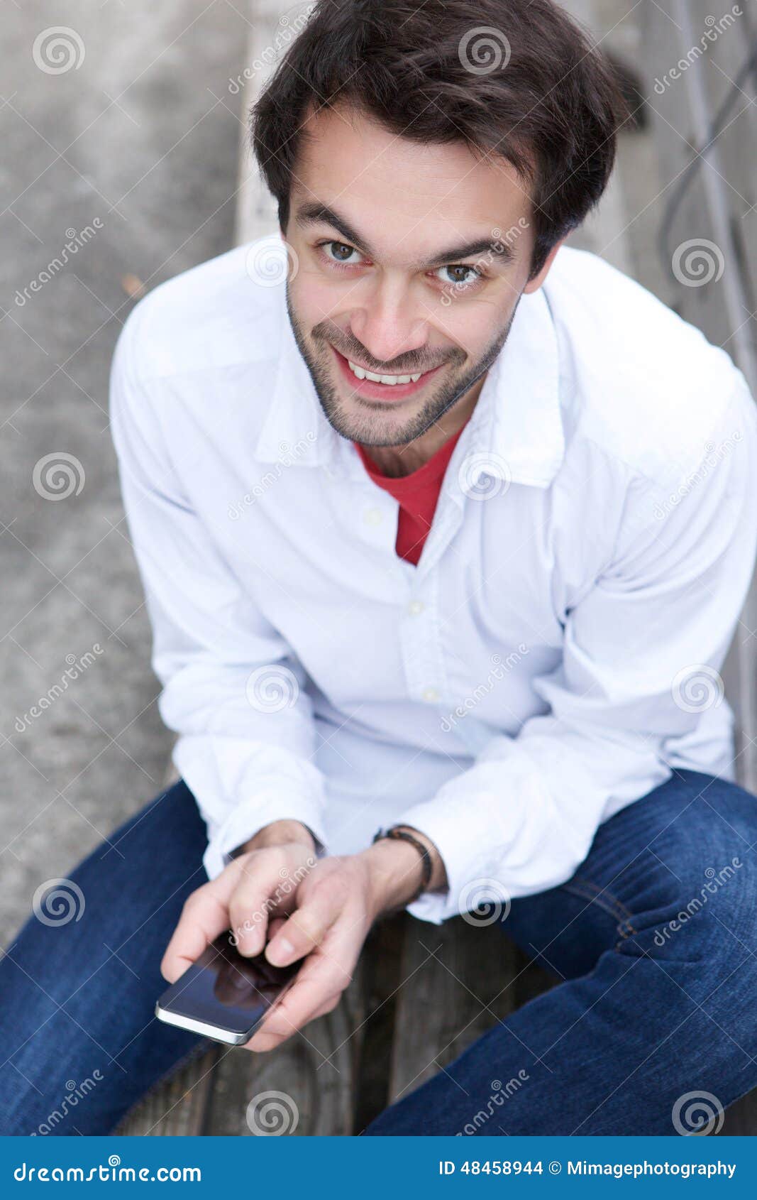 Young Man Smiling Outdoors with Mobile Phone Stock Photo - Image of ...