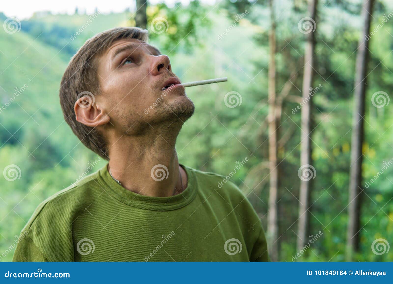 Young Man is Smoking Cigarettes in a Summer Forest in the Mountains ...
