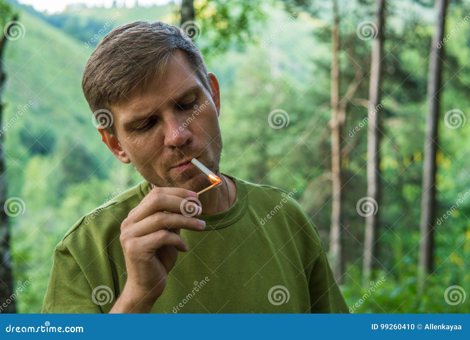 Young Man is Smoking Cigarettes in a Summer Forest in the Mountains ...