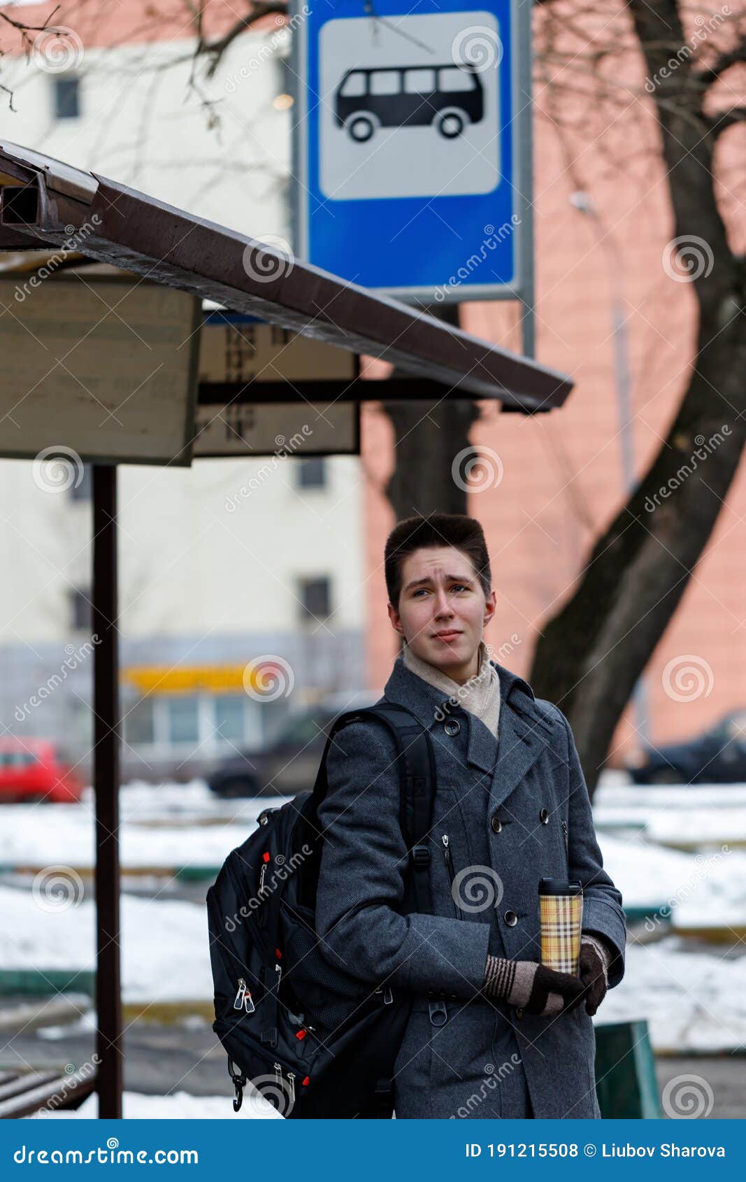 A Young Man is Standing at the Bus Stop and Waiting for the Bus Stock ...