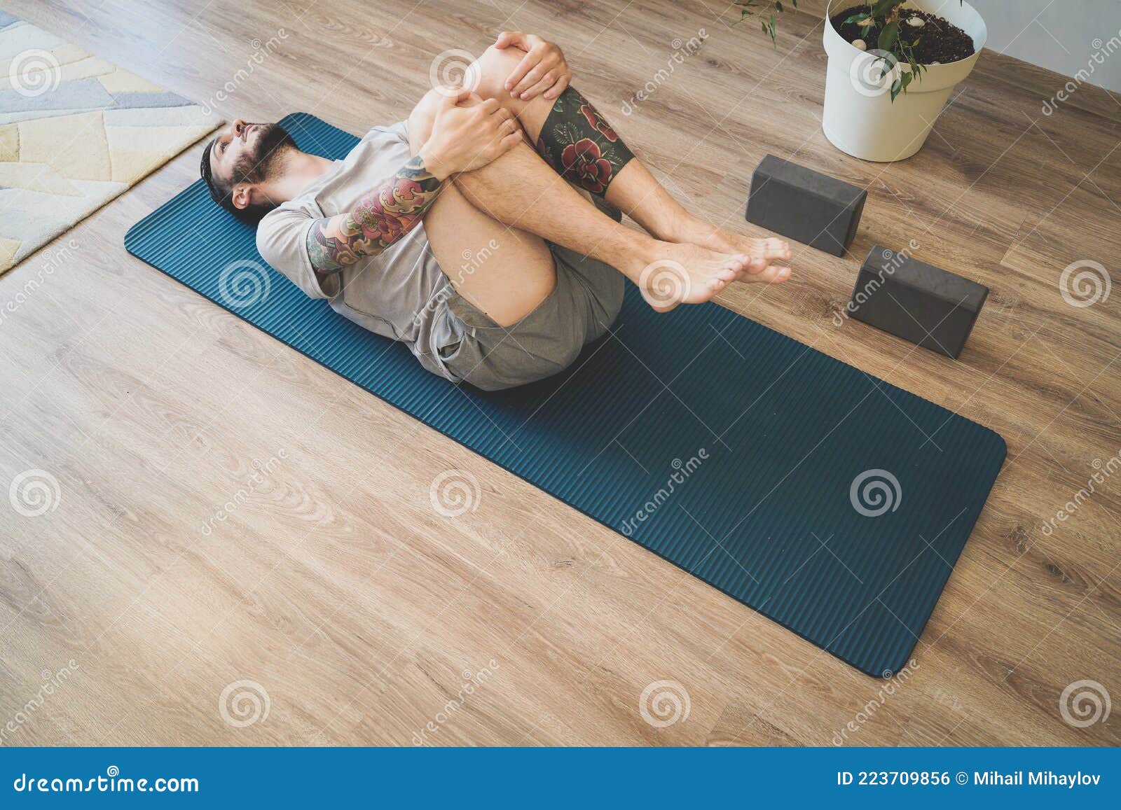 Young Man Starting the Day with Wind-Relieving Pose at Home Stock Photo ...