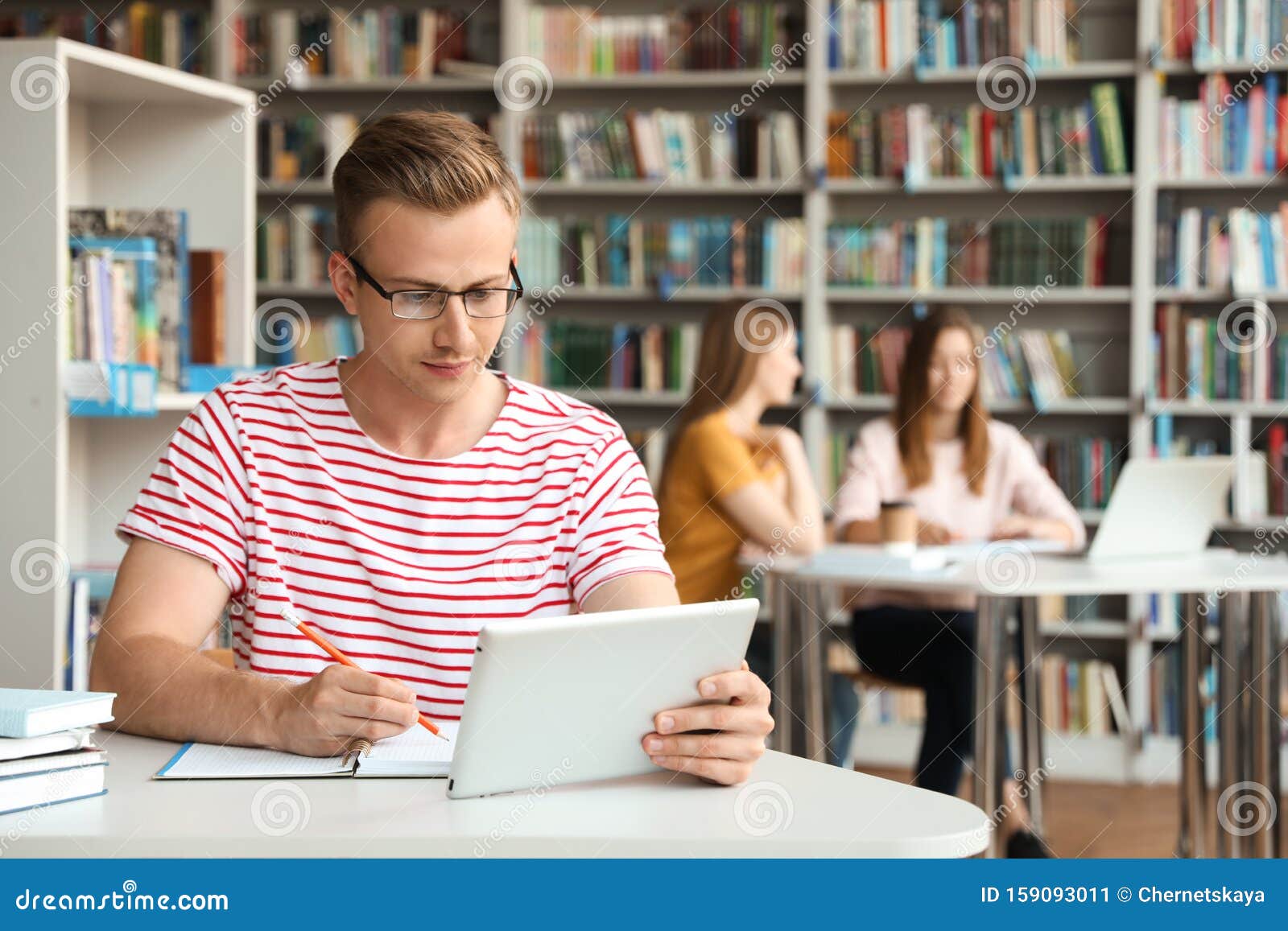 Young Man Studying with Tablet at Table in Library Stock Image - Image ...
