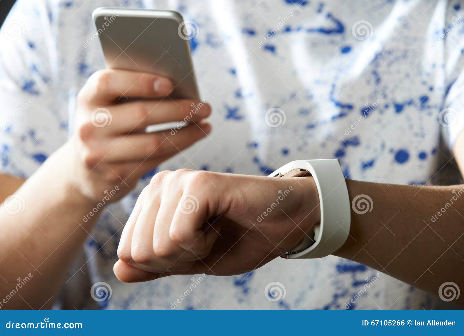 Young Man Synchronizing Smart Watch with Mobile Phone Stock Photo ...