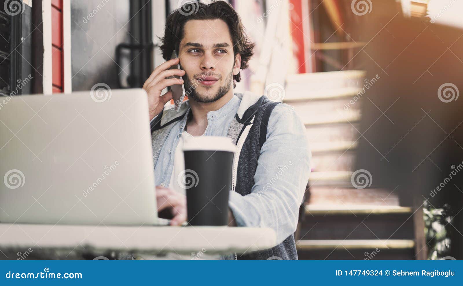 Young Man Talking Mobile Phone and Using Laptop Computer in Cafe Stock ...