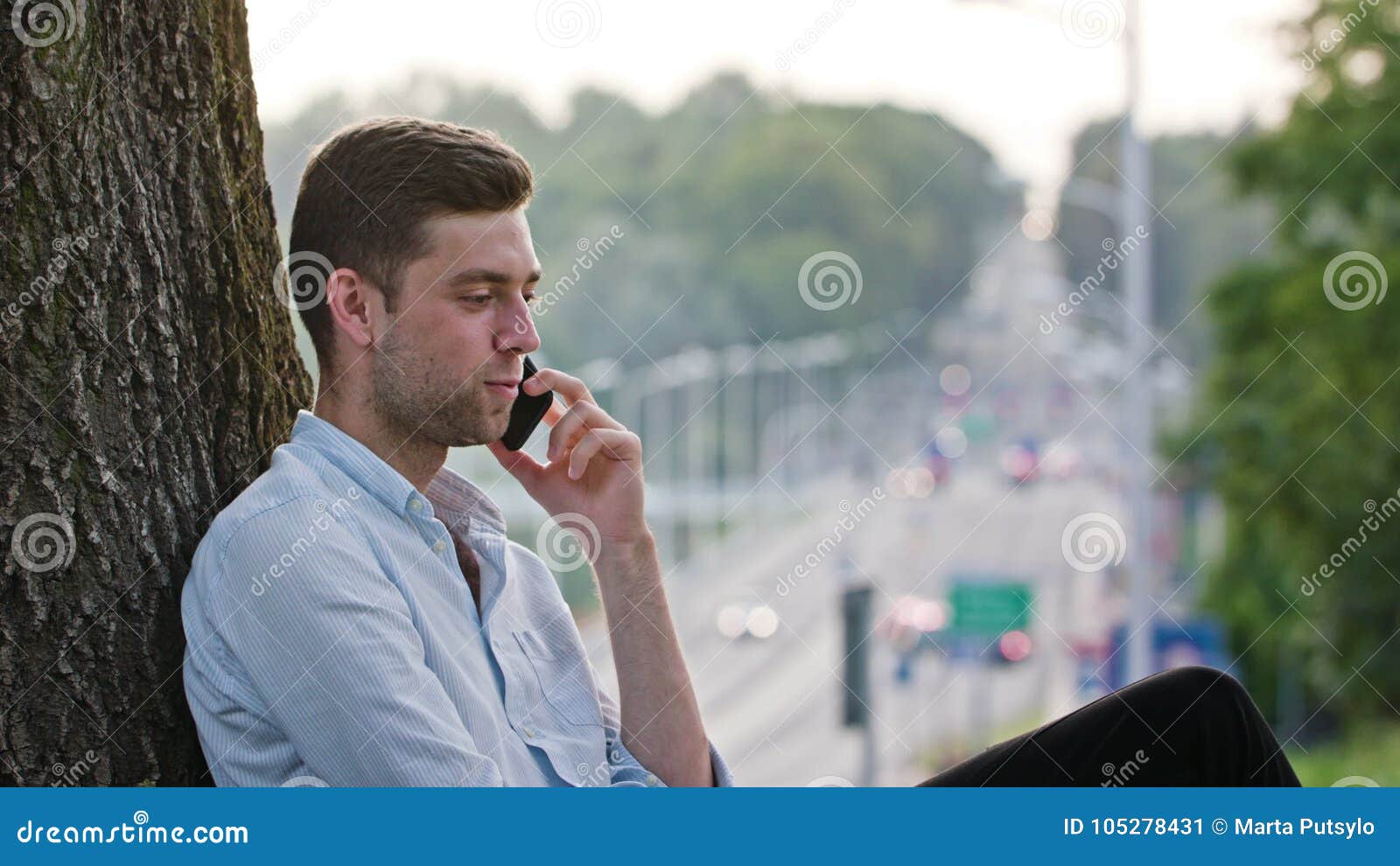 A Young Man Talking on the Phone Under a Tree Stock Image - Image of ...