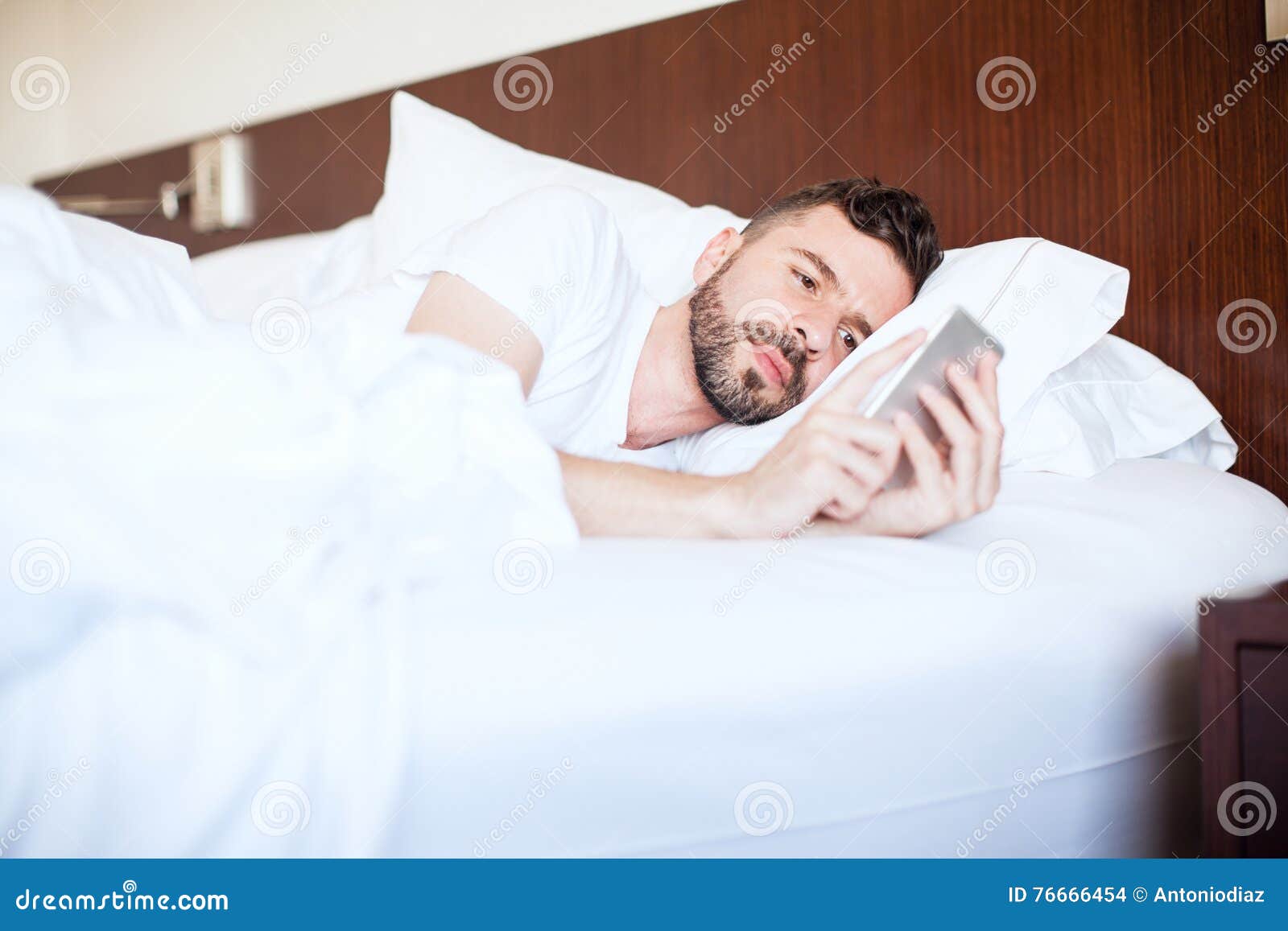 Young man texting in bed stock photo. Image of looking - 76666454
