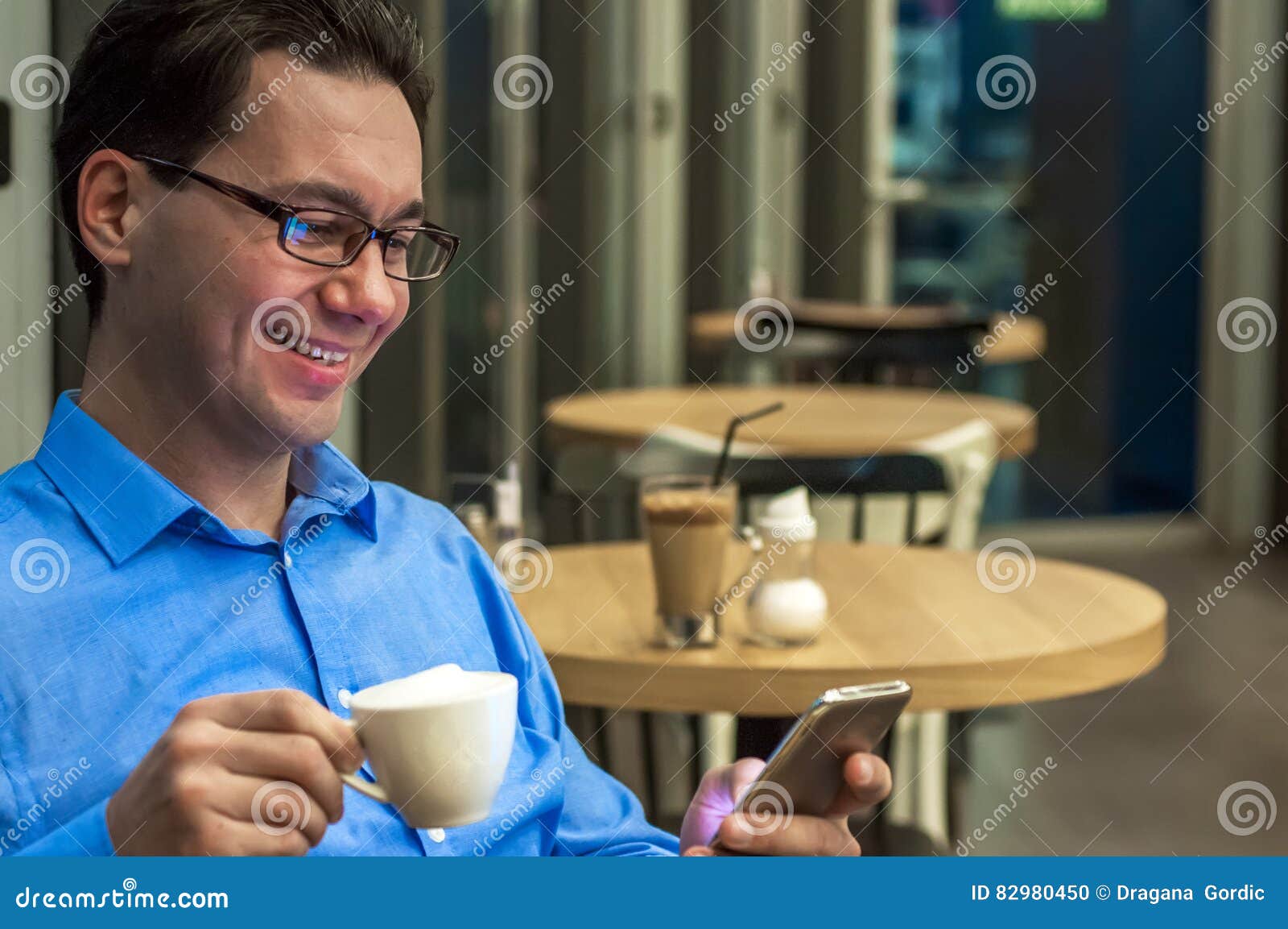 Young Man Texting in the Cafe. Happy Businessman Smiling and Texting on ...