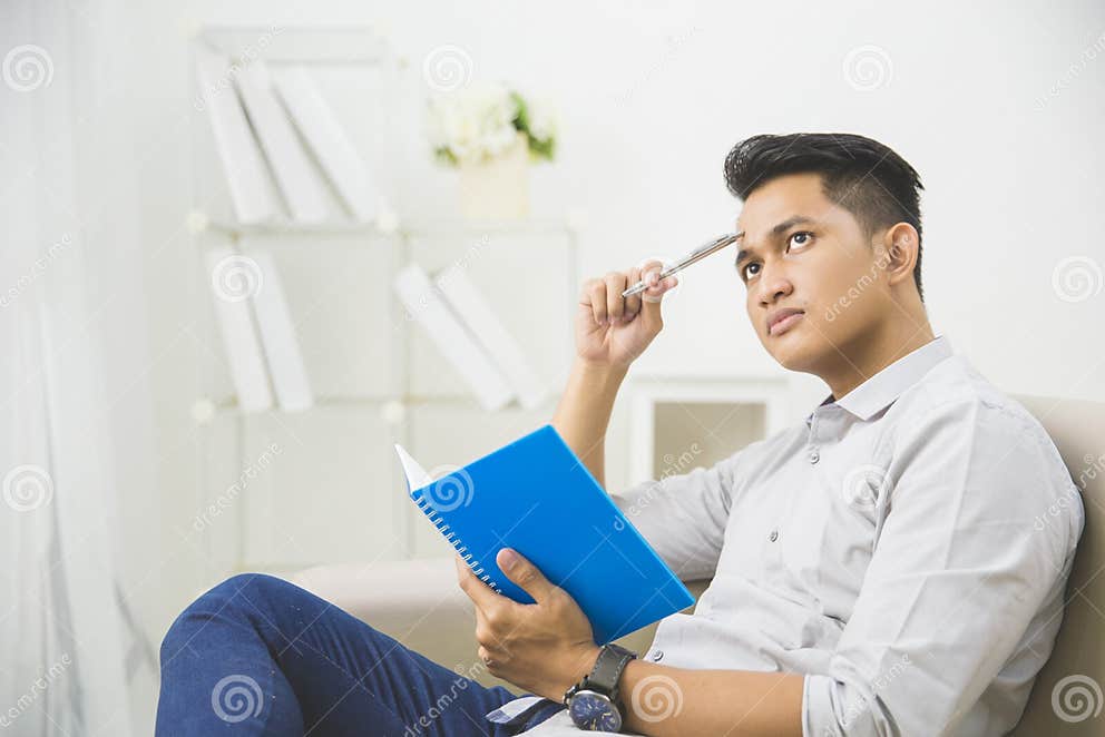 Young Man Thinking while Writing on a Book Stock Photo - Image of ...