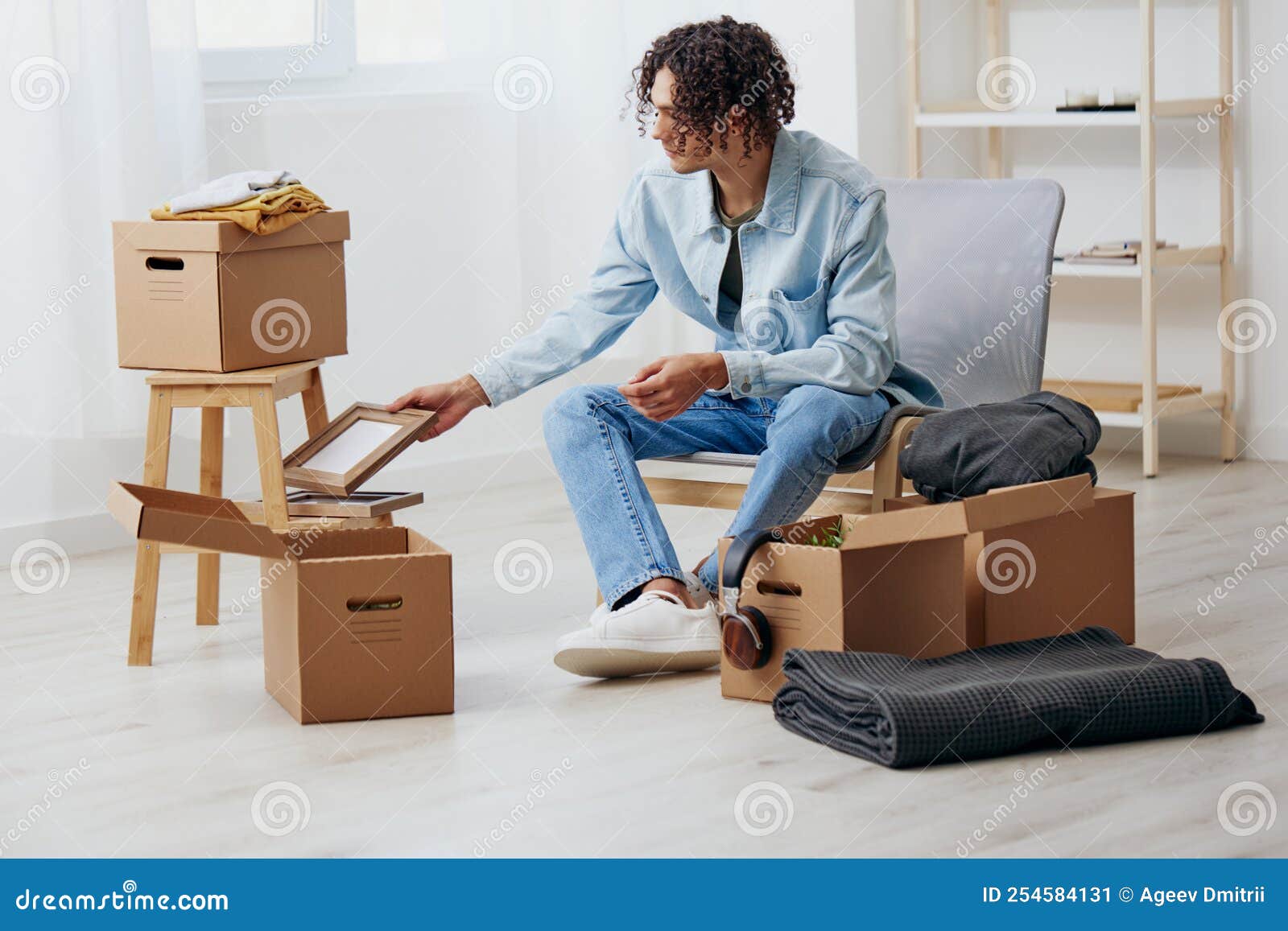 A Young Man Unpacking Things from Boxes in the Room Interior Stock ...