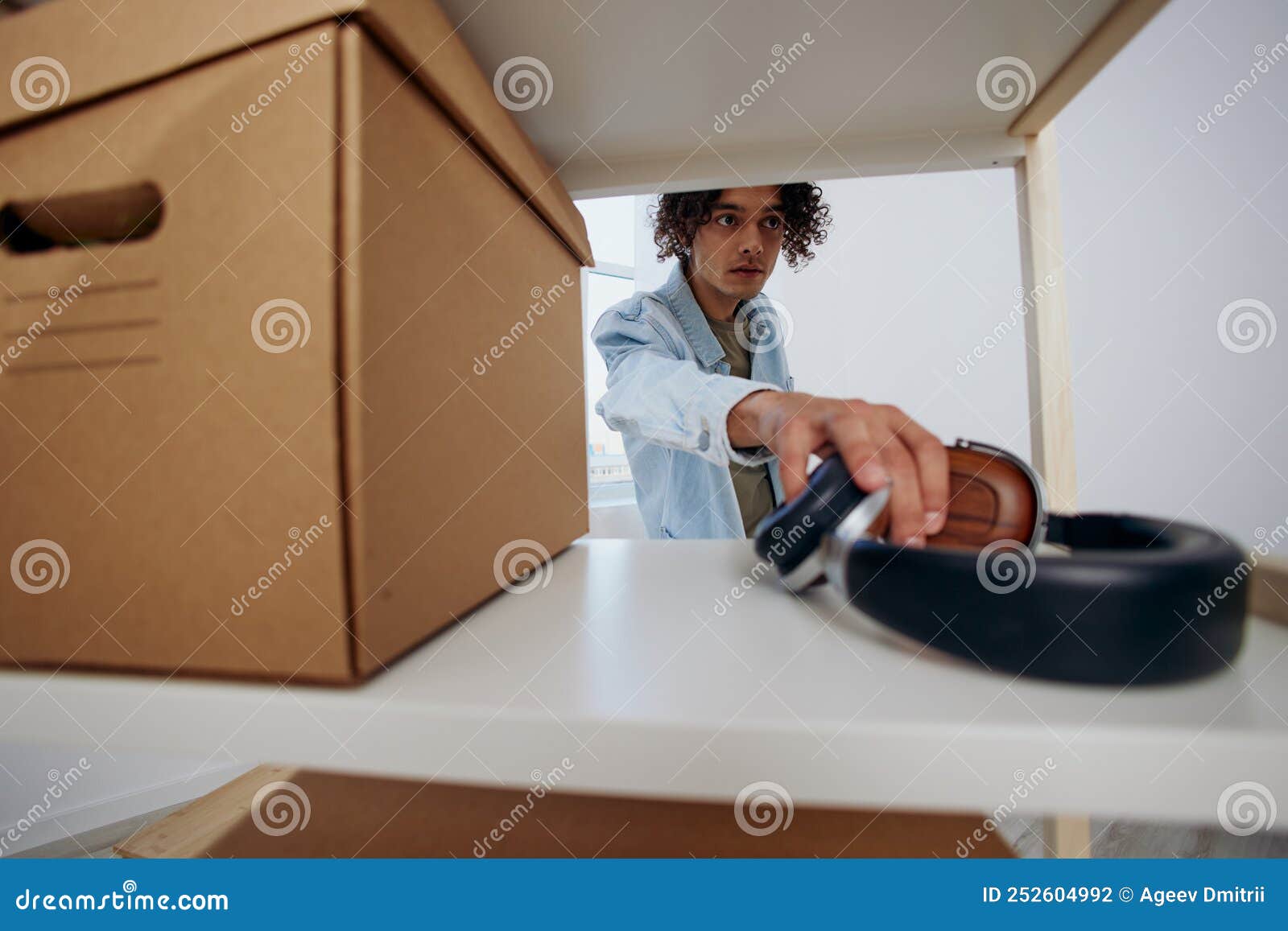 A Young Man Unpacking Things from Boxes in the Room Sorting Things Out ...