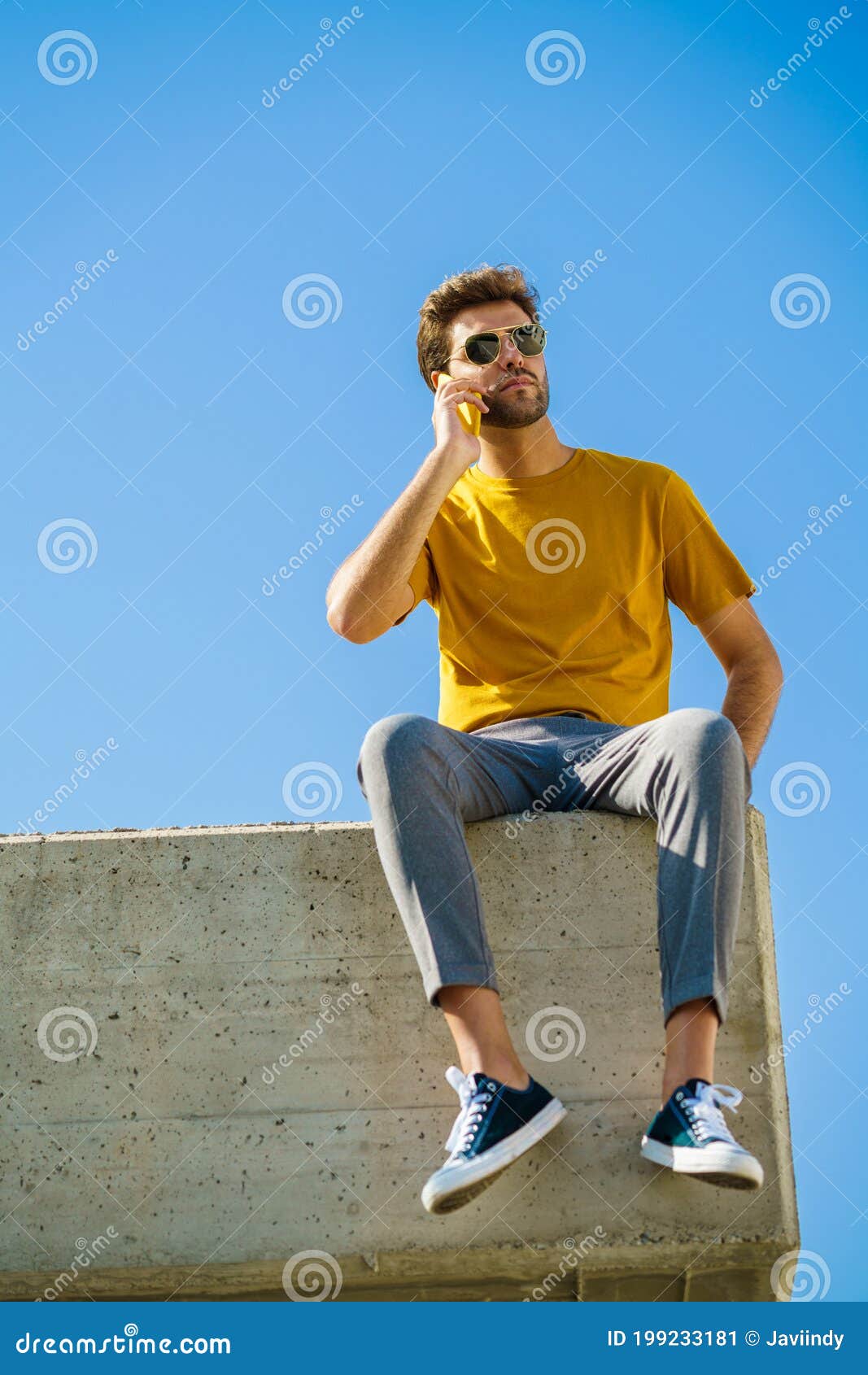Young Man Using His Smartphone Sitting on a Ledge Outside Stock Image ...