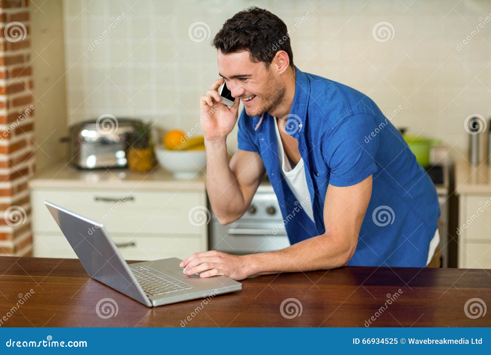 Young Man Using Laptop and Talking on Phone Stock Image - Image of ...
