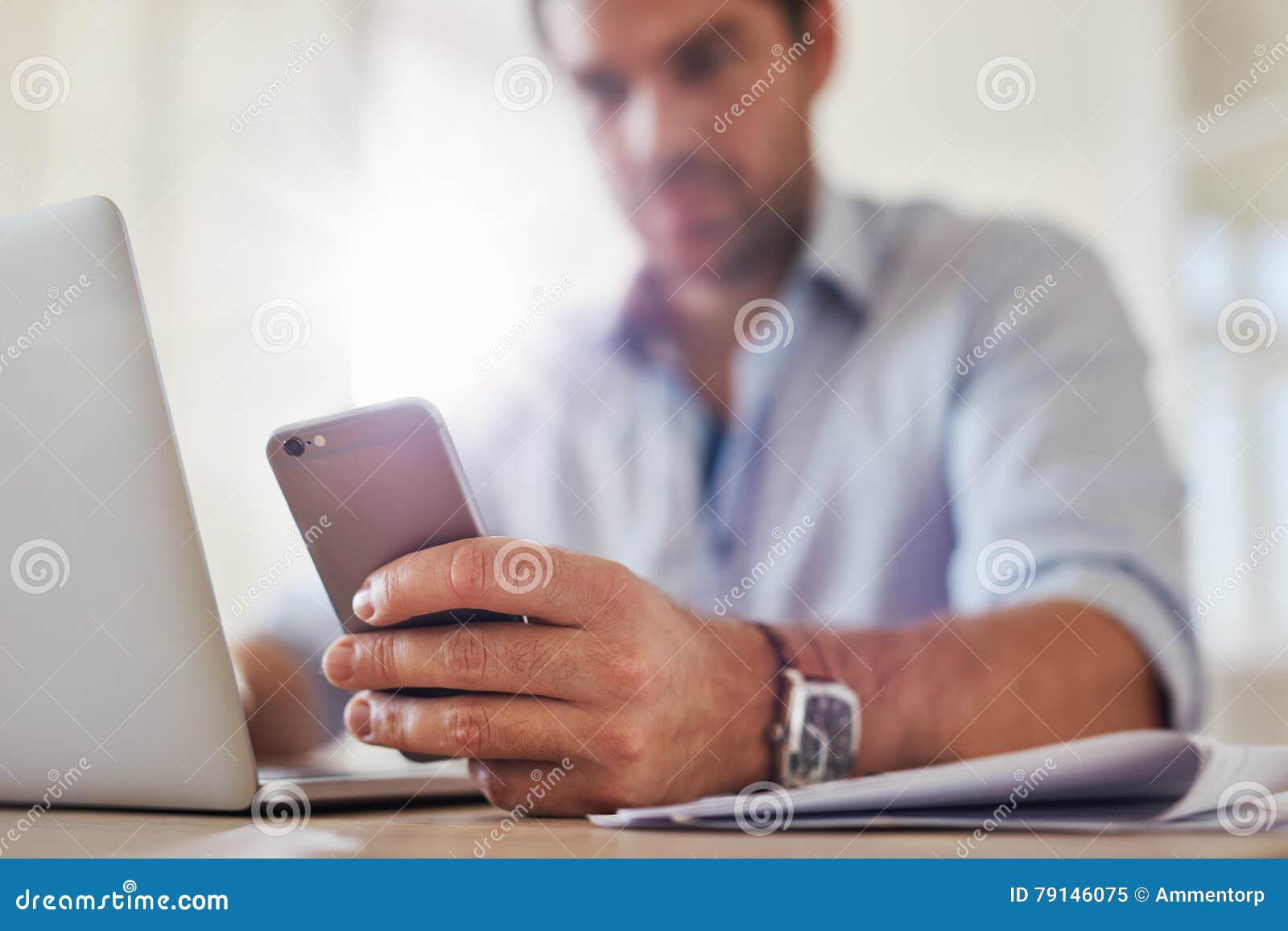 Young Man Using Mobile Phone while Working on Laptop Stock Image ...