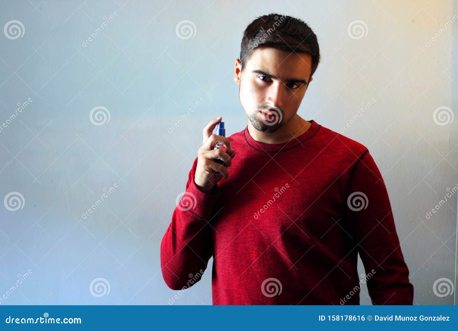 Young Man Using Perfume or Cologne on a Gray Background Stock Photo ...