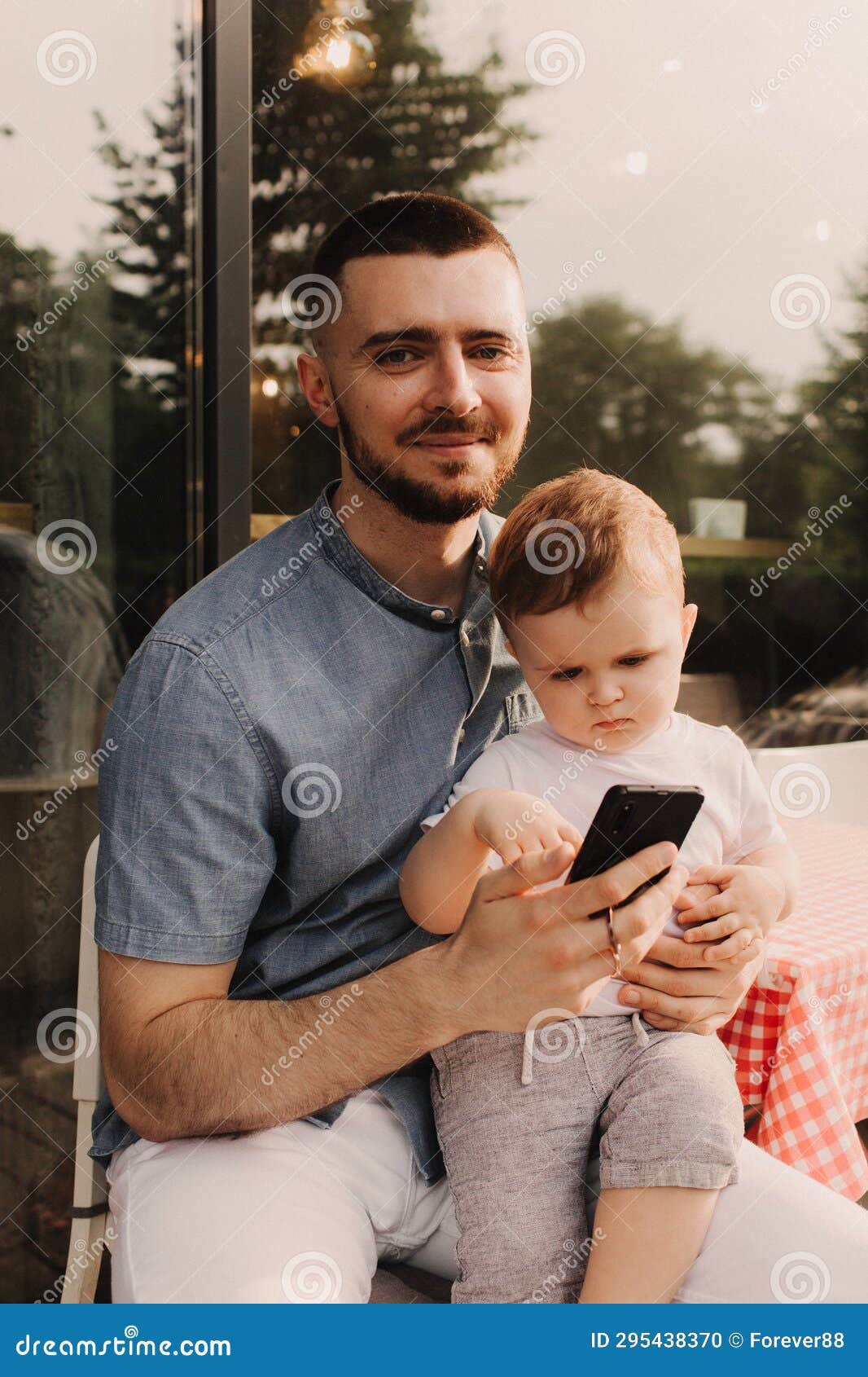 Young Man Using a Phone Mobile for Work and Holding His Son on His Hand ...